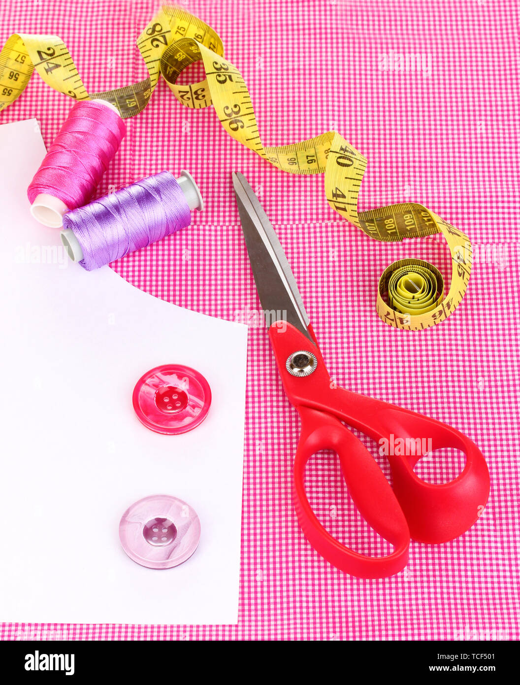 Scissors, threads, buttons, measuring tape and pattern on fabric ...