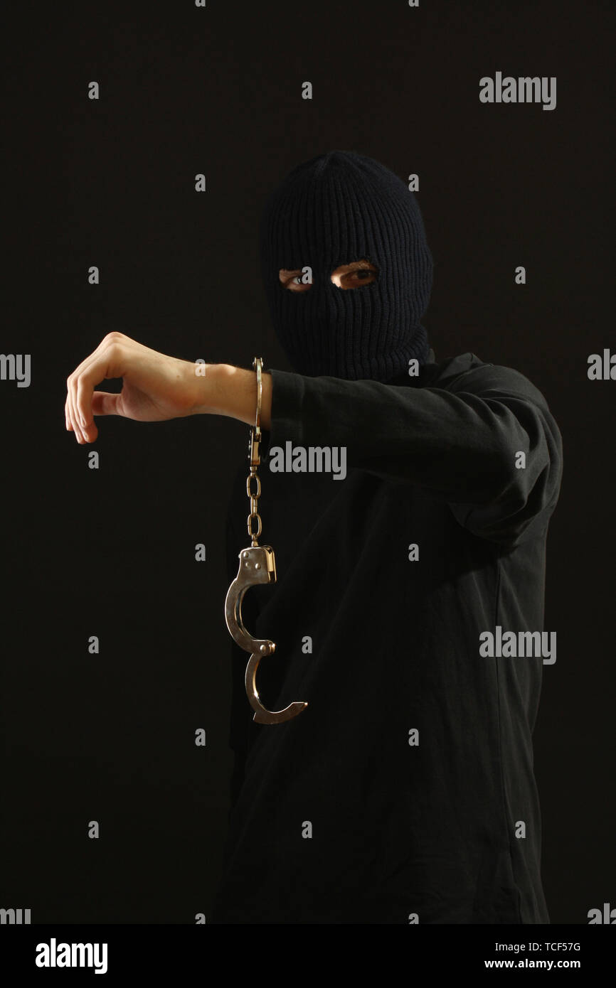 Bandit in black mask with handcuffs isolated on black Stock Photo - Alamy