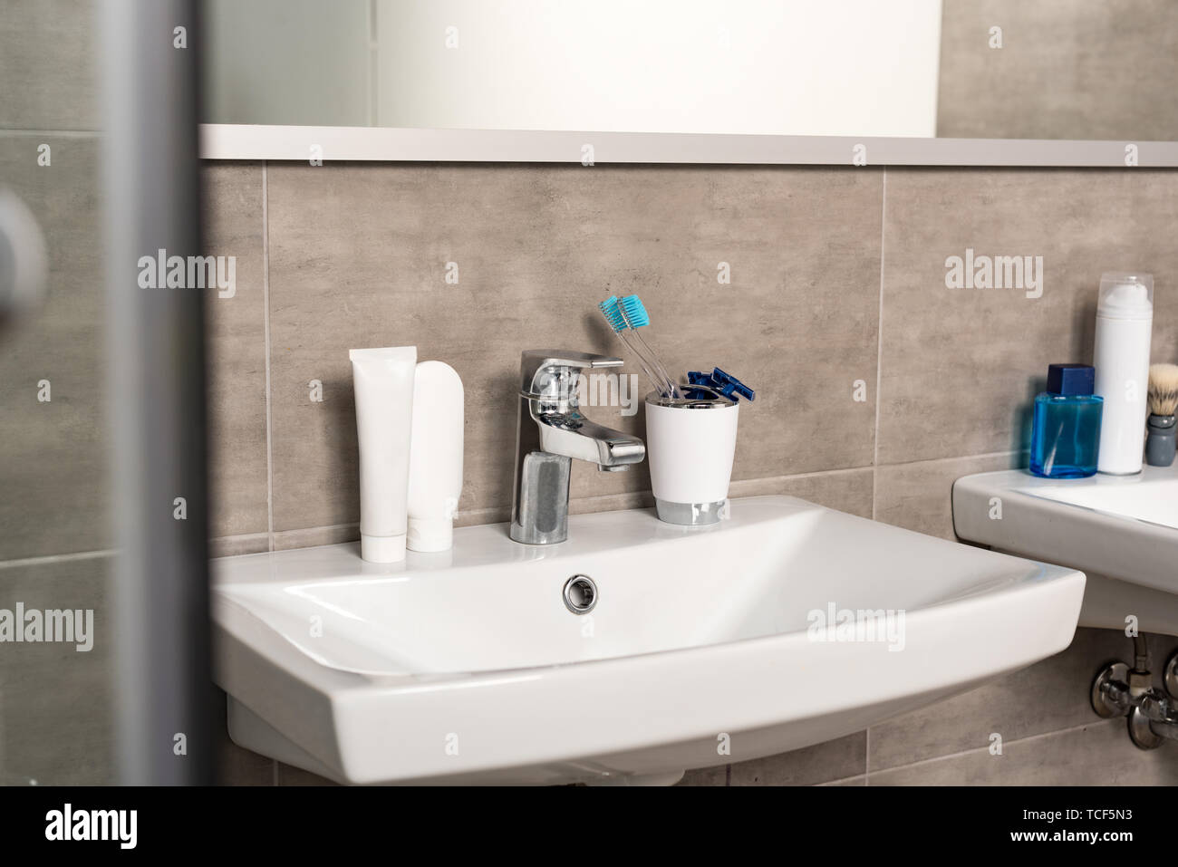 toothbrushes, toothpaste and shaving razors on sink in bathroom Stock ...