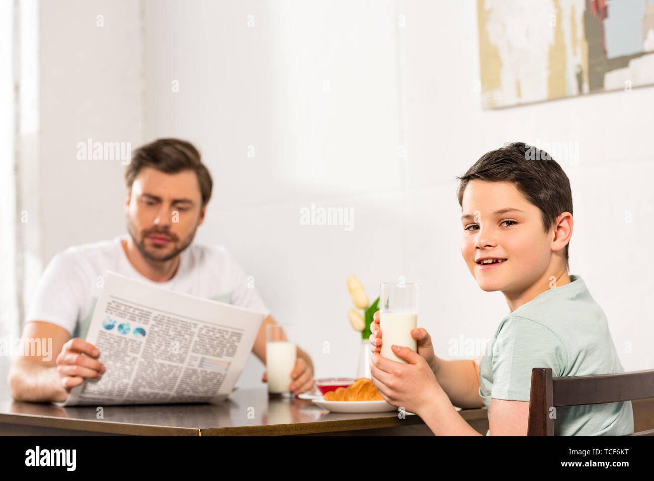 father with newspaper and smiling son having breakfast together Stock ...