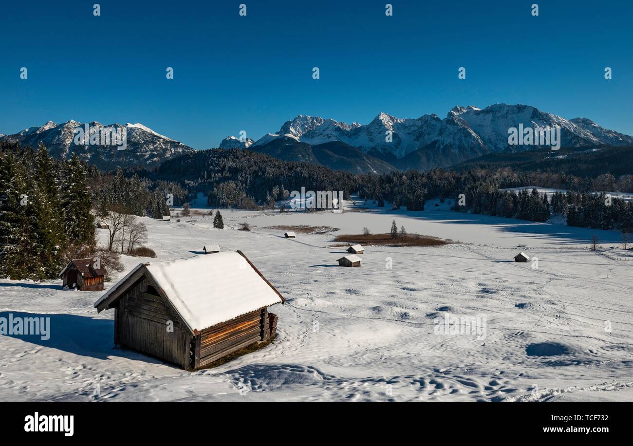 Haystack in snow-covered landscape, frozen Lake Geroldsee in winter in ...