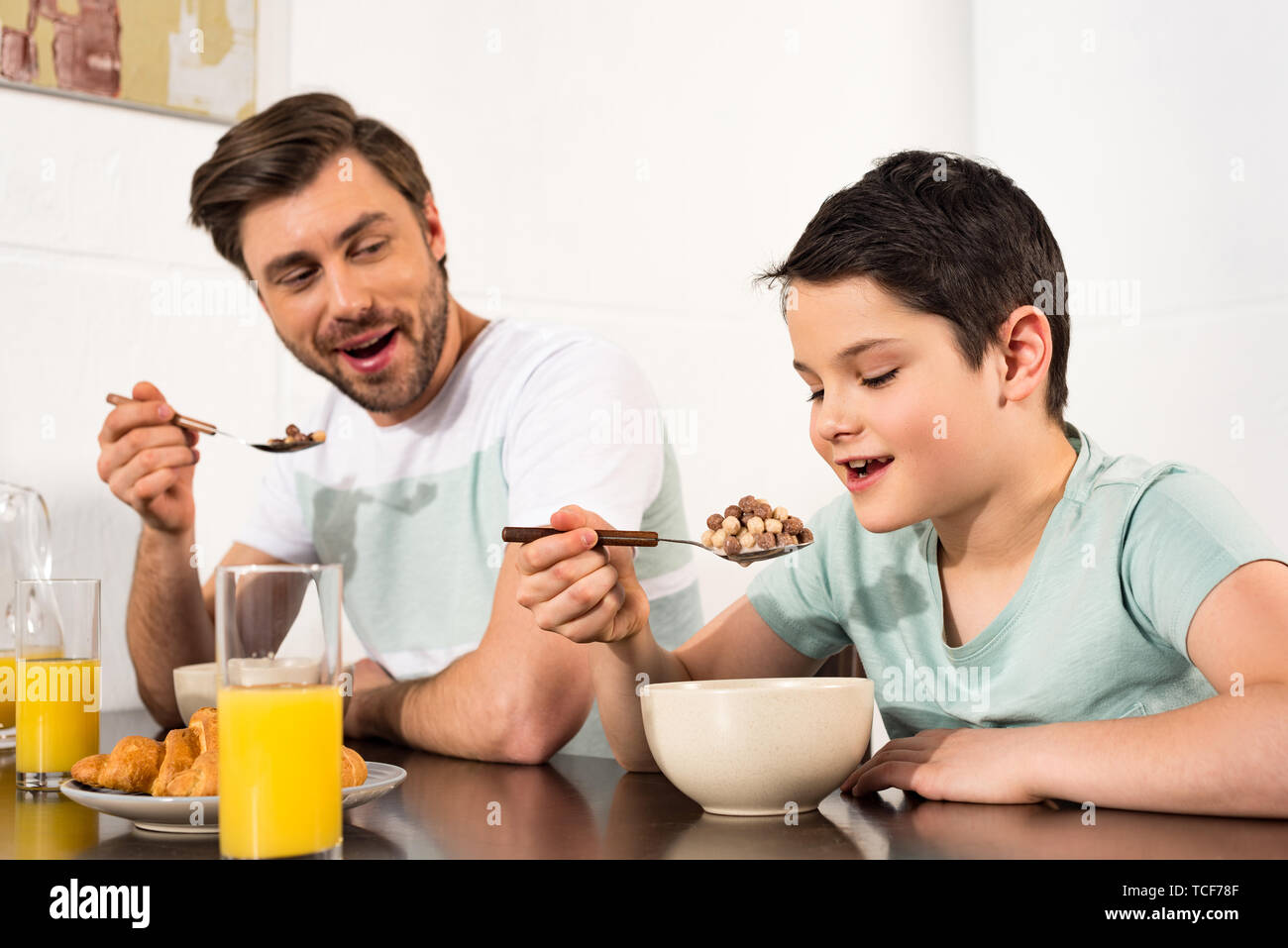 smiling father and son eating breakfast cereal in kitchen Stock Photo ...