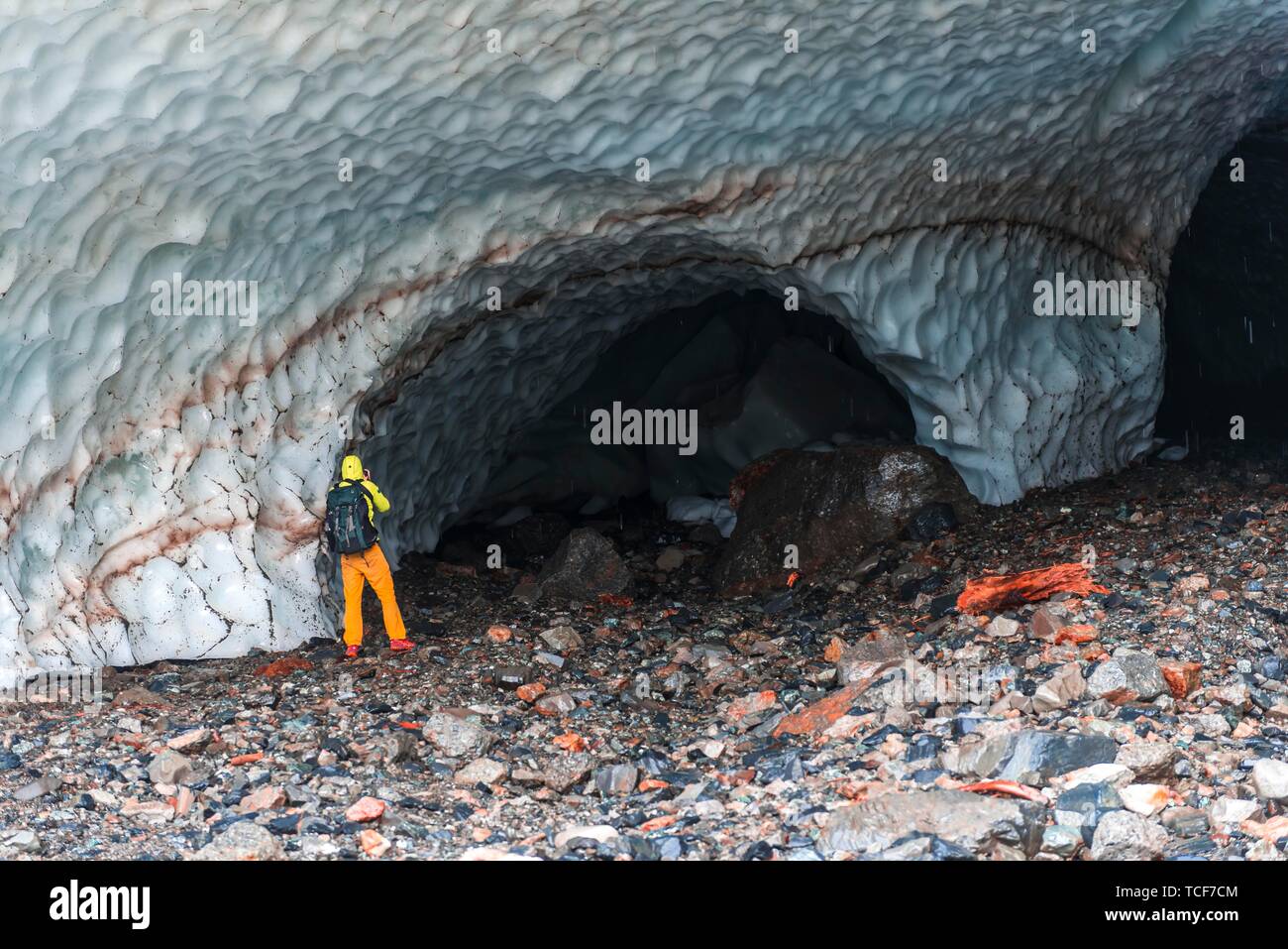 Man at the entrance of an ice cave of a glacier, Big Four Ice Caves ...