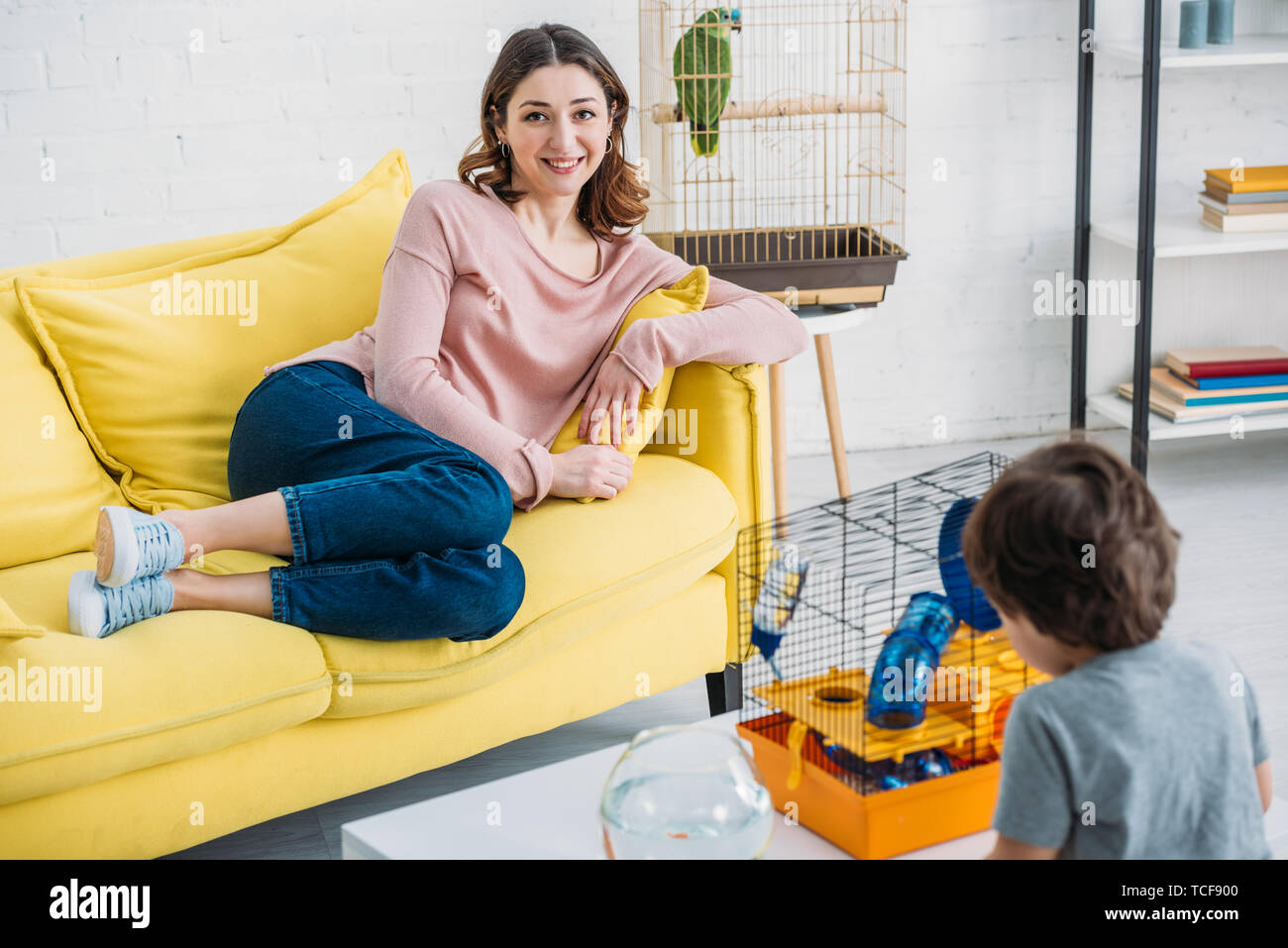selective focus at smiling mother resting on yellow sofa while cute son ...