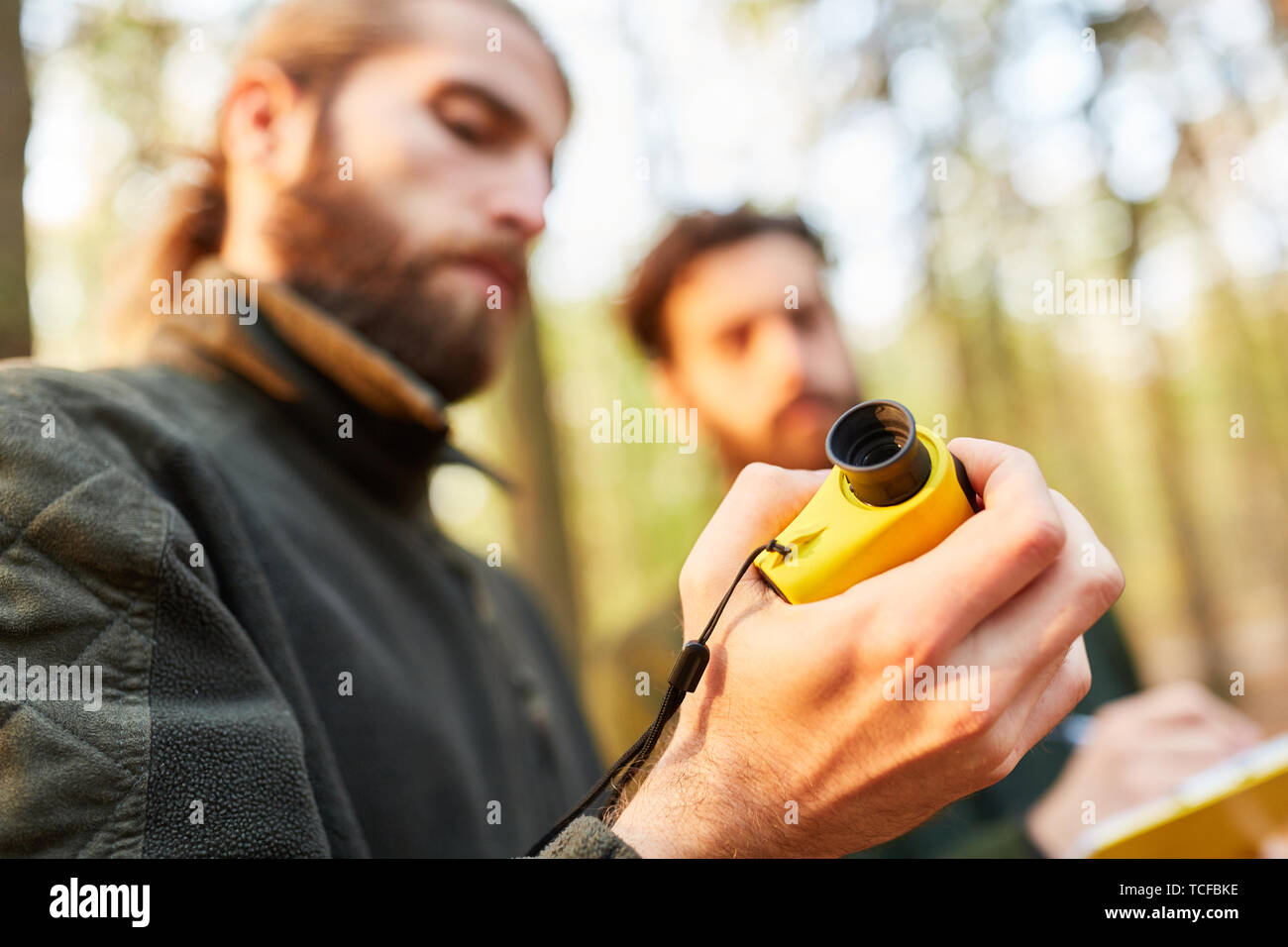 Two foresters work with the rangefinder to measure the height of the ...