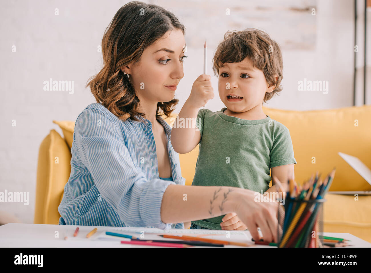 amazed kid holding color pencil while drawing with mom Stock Photo - Alamy