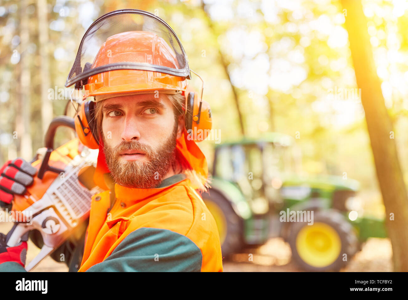 Forest worker as a woodcutter with chainsaw and work safety in the ...