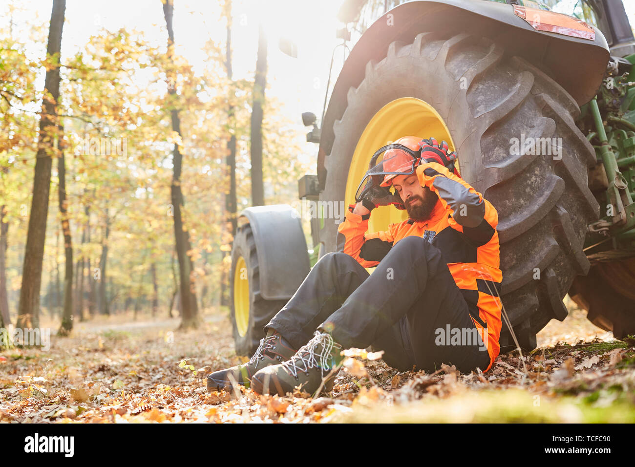 Forest worker sits tired and exhausted on the tractor after the harvest ...