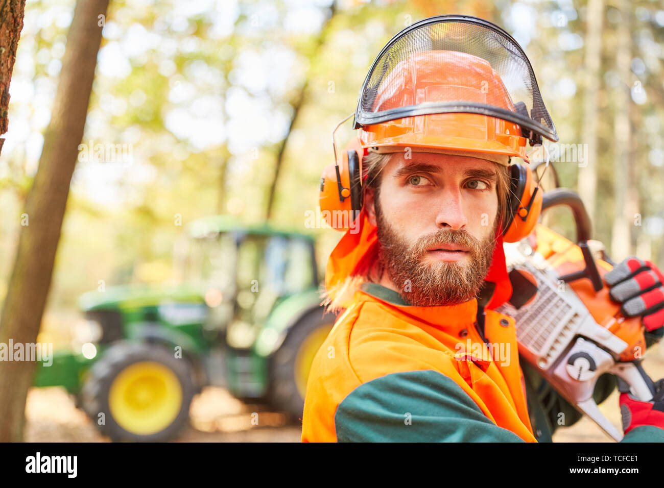 Man as a forest worker as a lumberjack with chainsaw and in protective ...