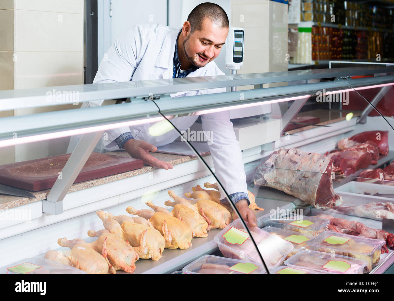 positive american male shop assistant selling kosher chicken at counter ...