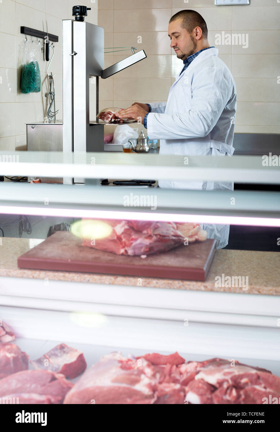 Portrait of handsome male butcher in kosher section at supermarket ...