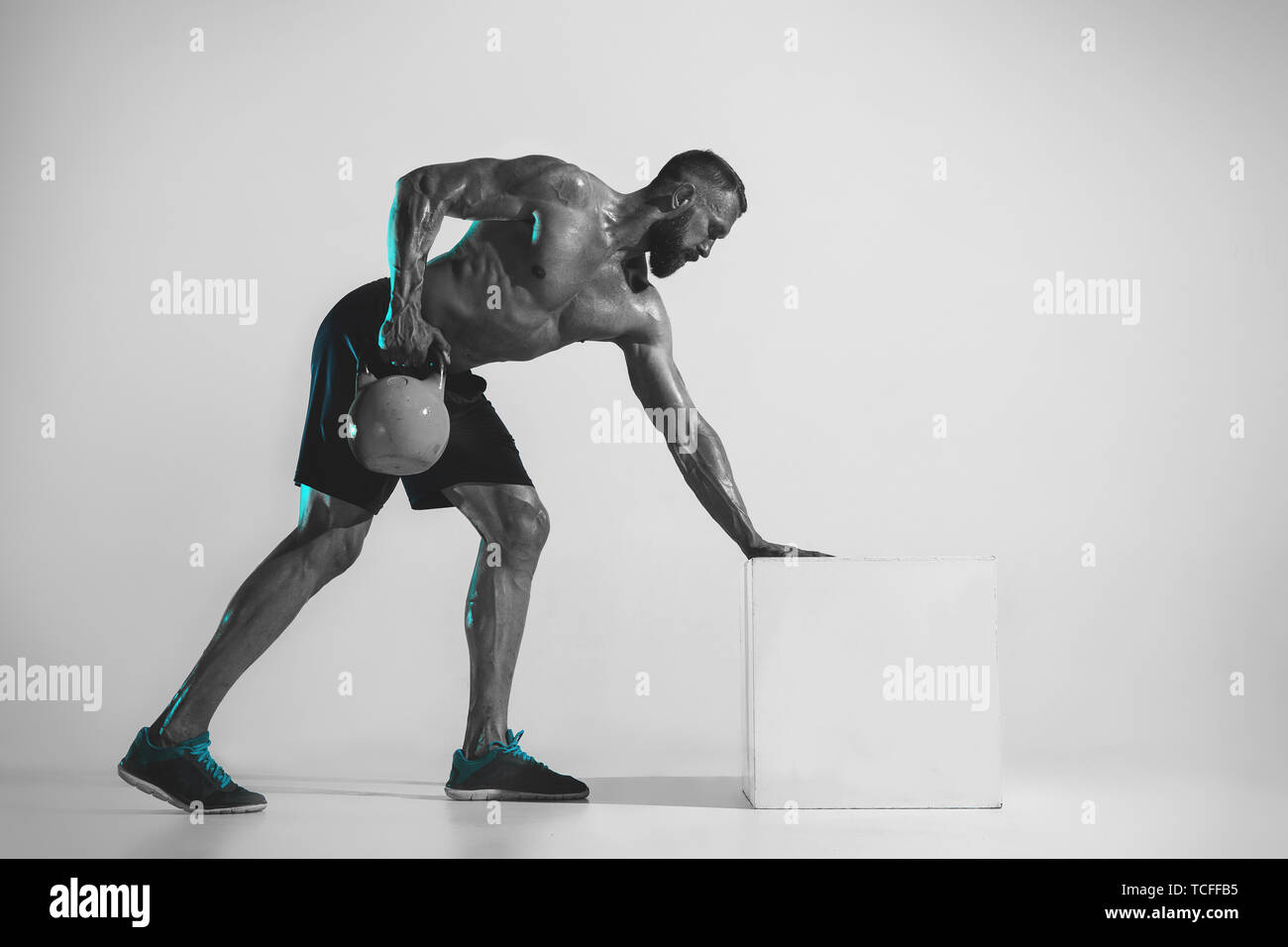 Reliable support. Young caucasian bodybuilder training over studio ...