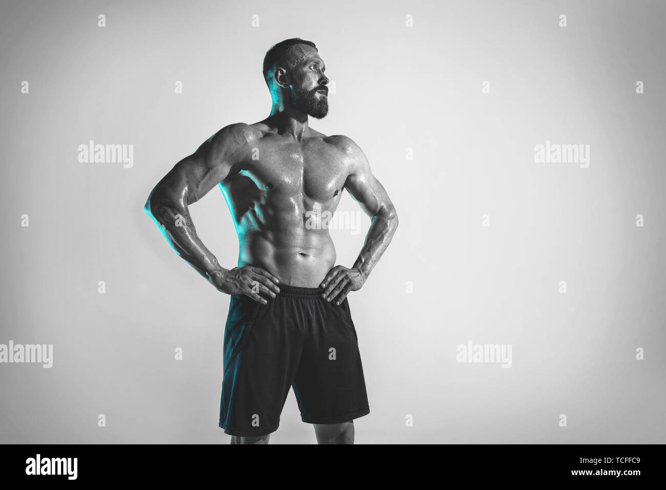 Young caucasian bodybuilder training over studio background in neon ...