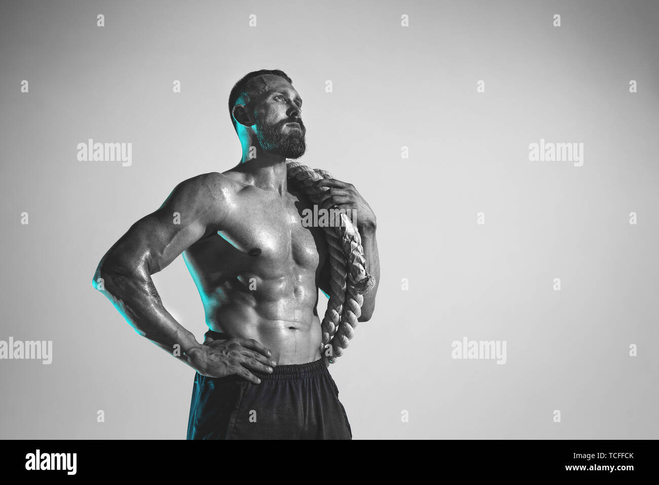 Young caucasian bodybuilder training over studio background in neon ...
