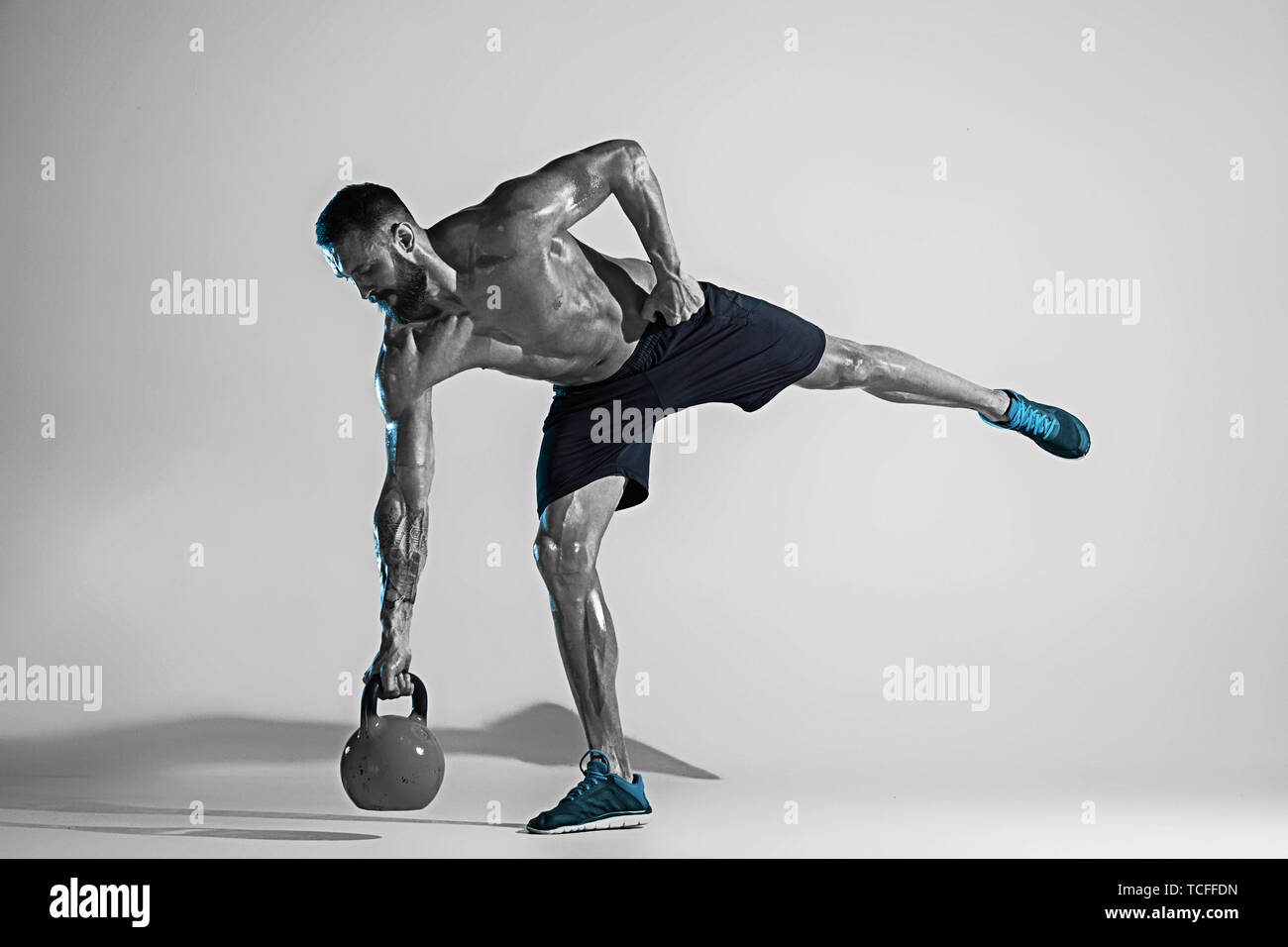 Like a stone. Young caucasian bodybuilder training over studio ...