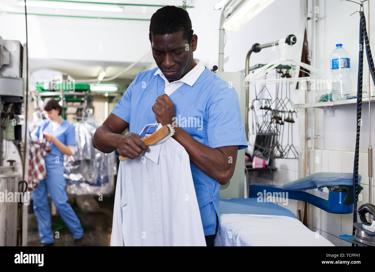 Focused African-American man dry cleaning clothes in laundry Stock ...