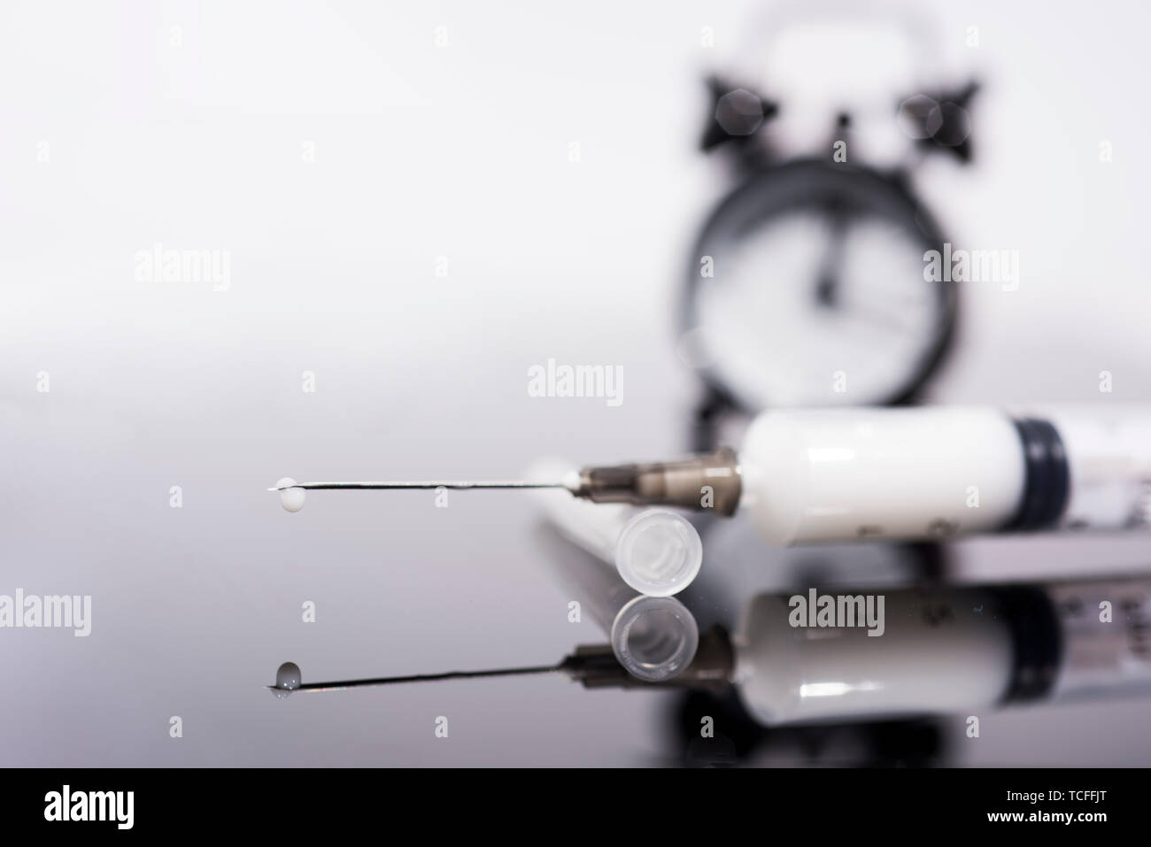 Vaccination time. Vaccine in vial with syringe on clock background ...