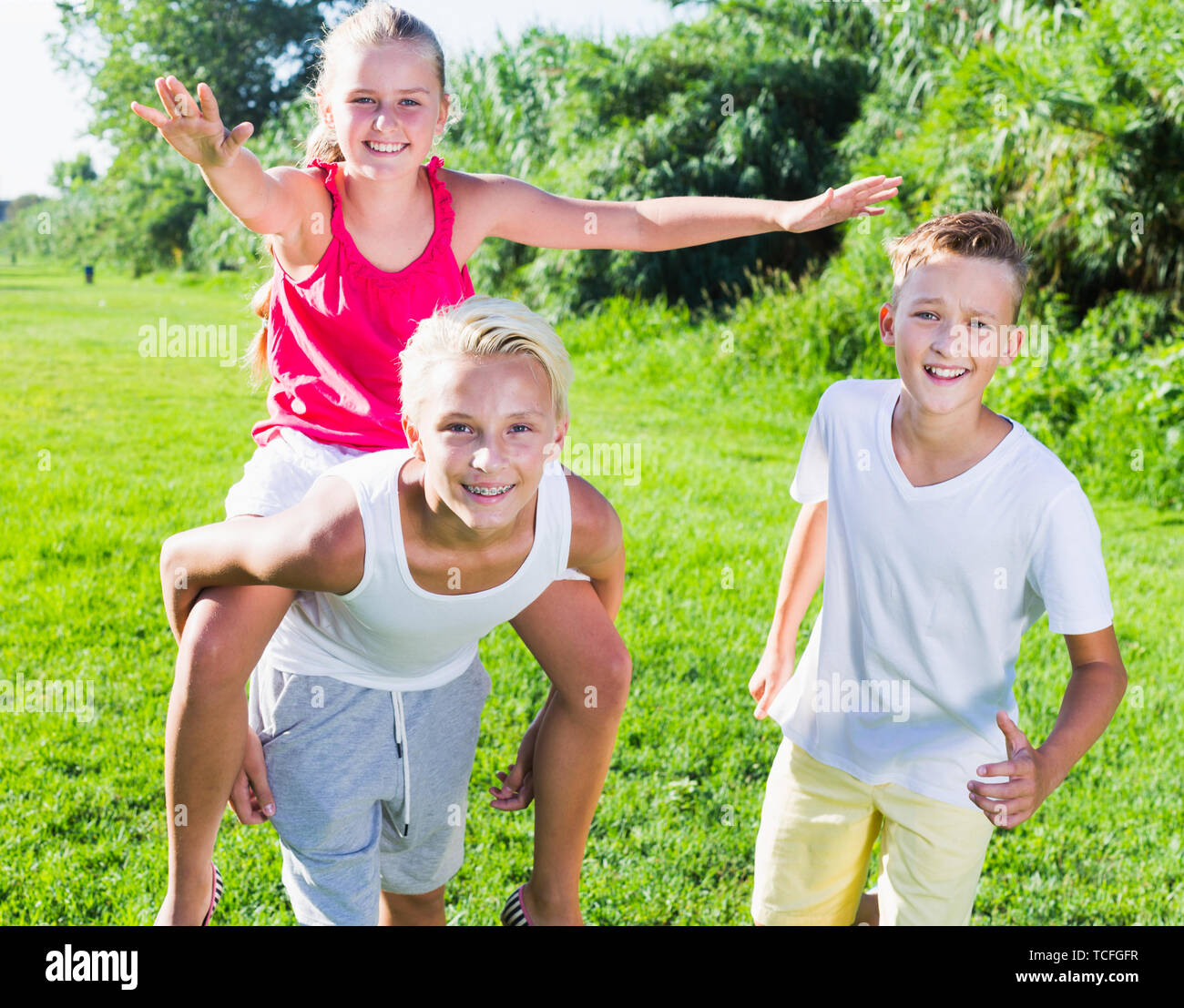 Happy children running together outdoors, boy carrying girl on back ...