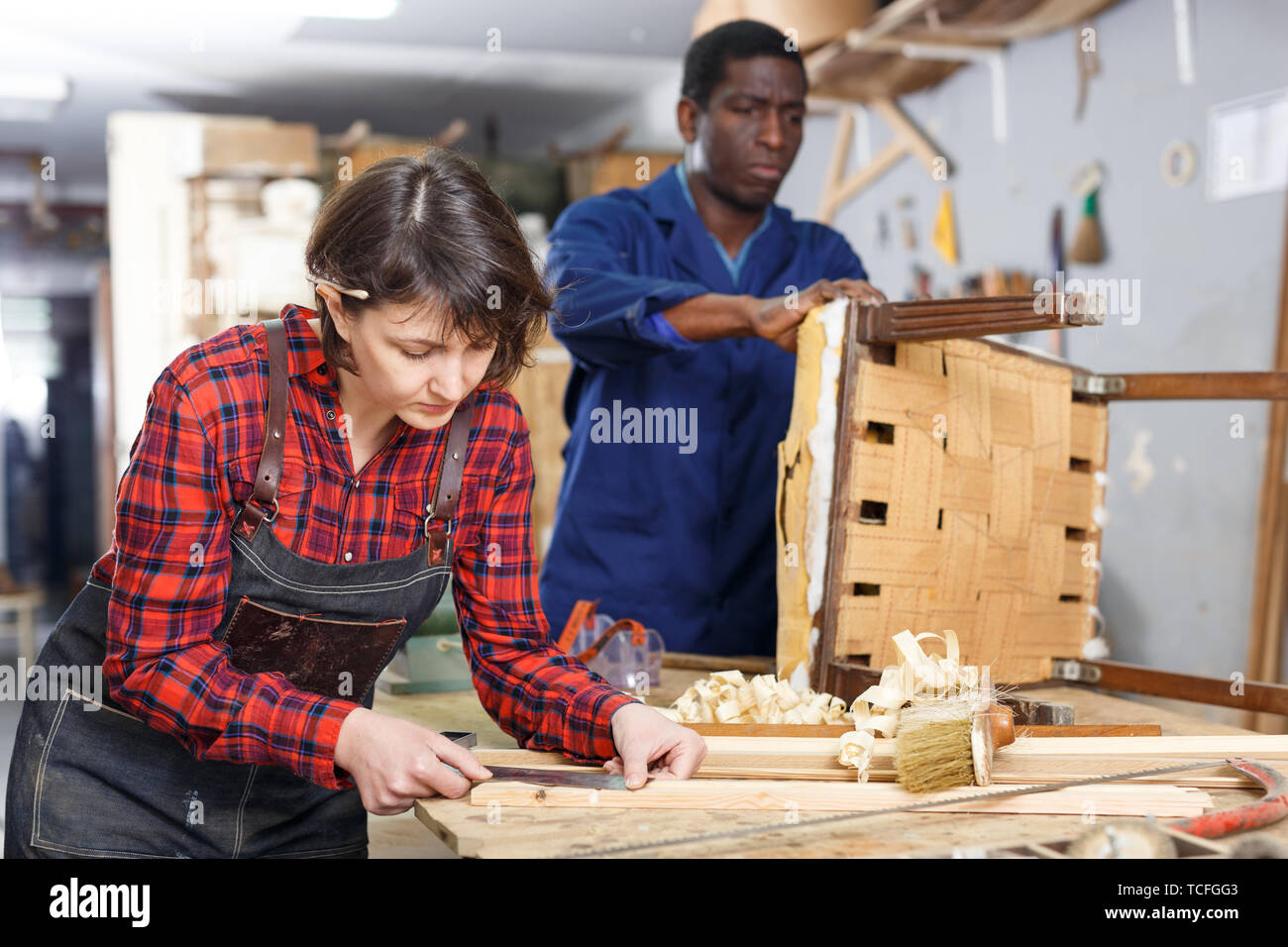 Woman and man carpenters using tools for restoration wooden chair in ...