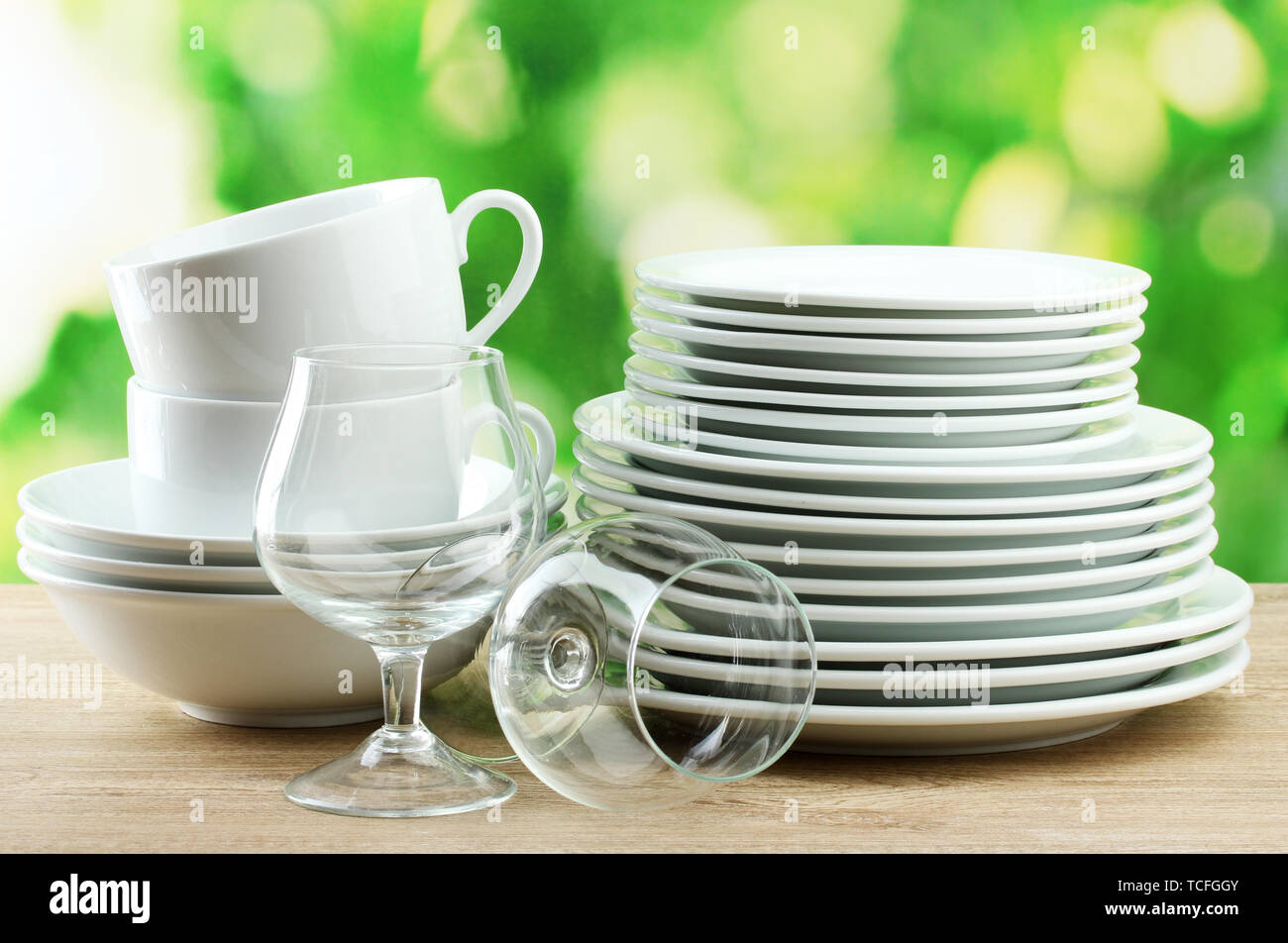 Clean dishes on wooden table on green background Stock Photo - Alamy