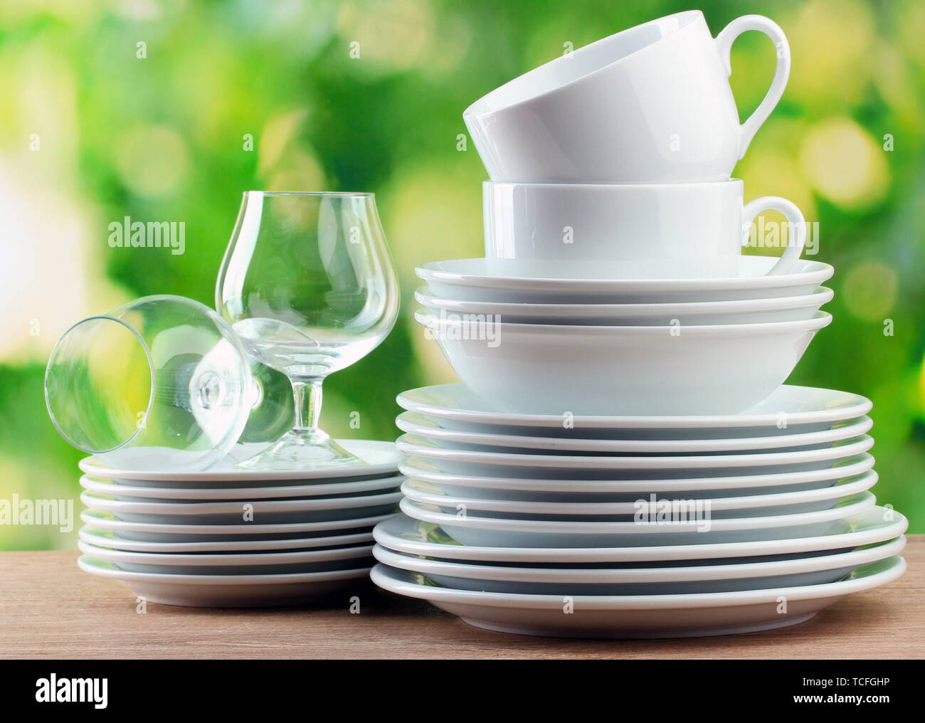 Clean dishes on wooden table on green background Stock Photo - Alamy
