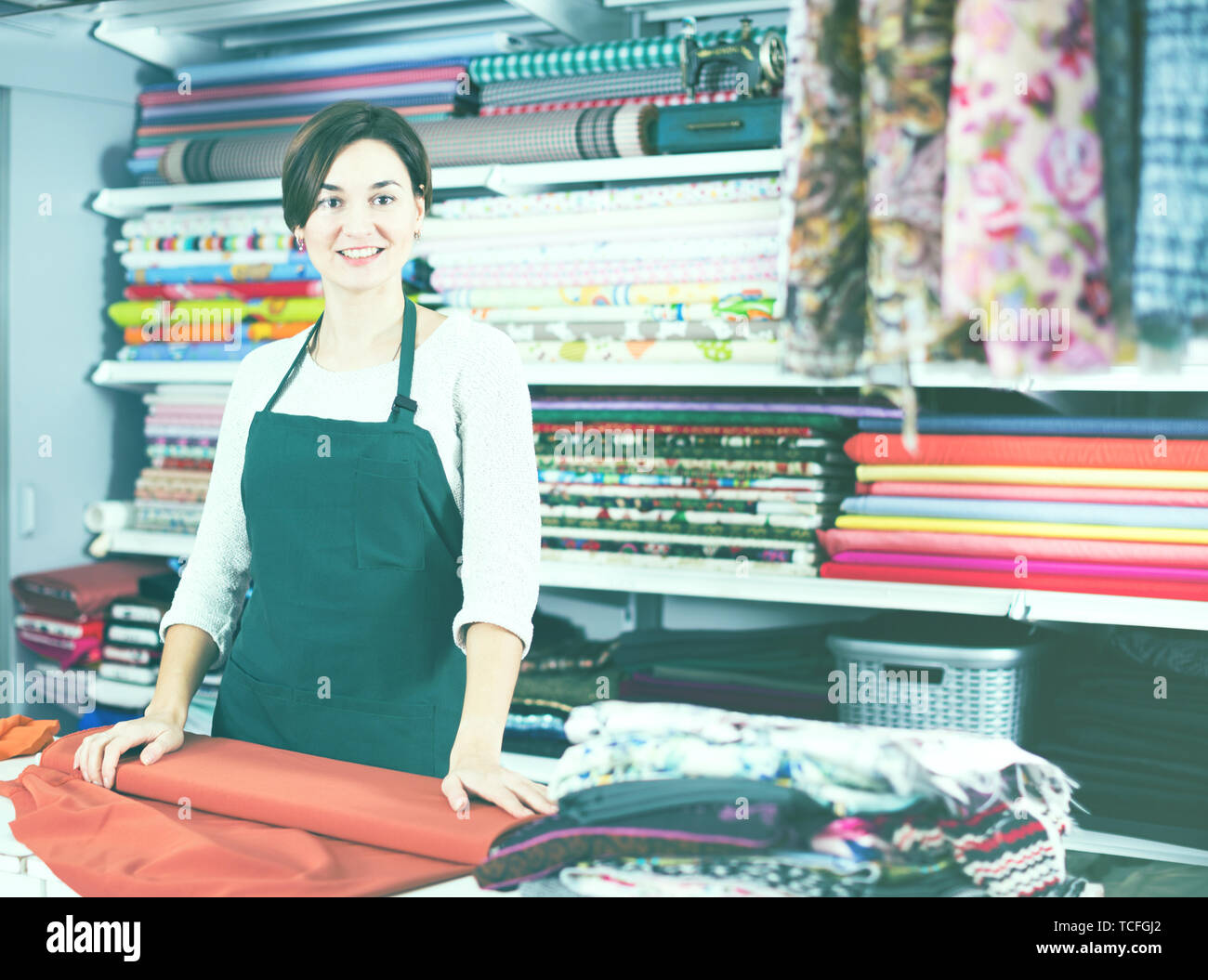 Young woman seller measuring square of cloth at drapery shop Stock ...