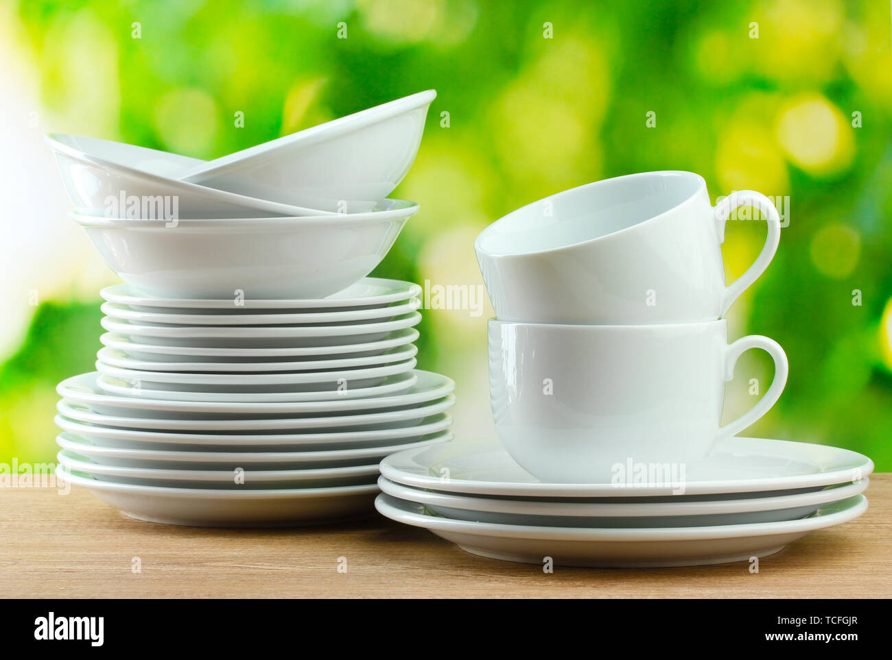 Clean dishes on wooden table on green background Stock Photo - Alamy