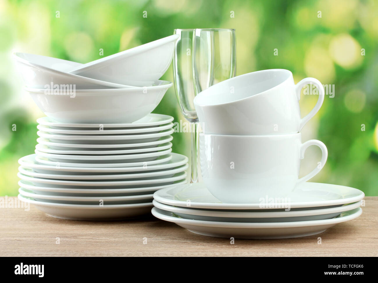 Clean dishes on wooden table on green background Stock Photo - Alamy