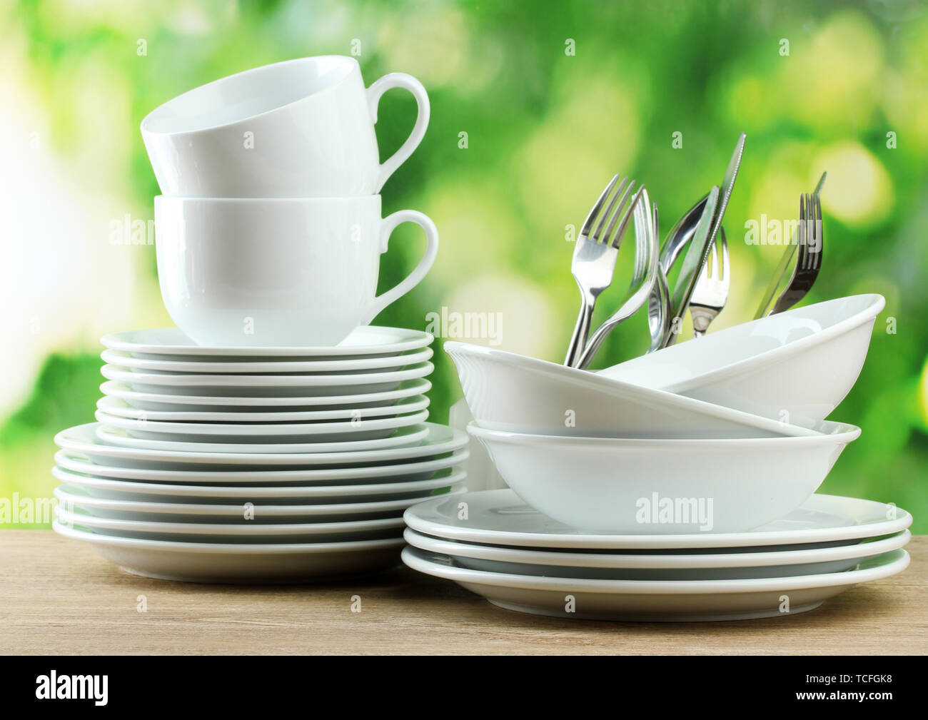 Clean dishes on wooden table on green background Stock Photo - Alamy
