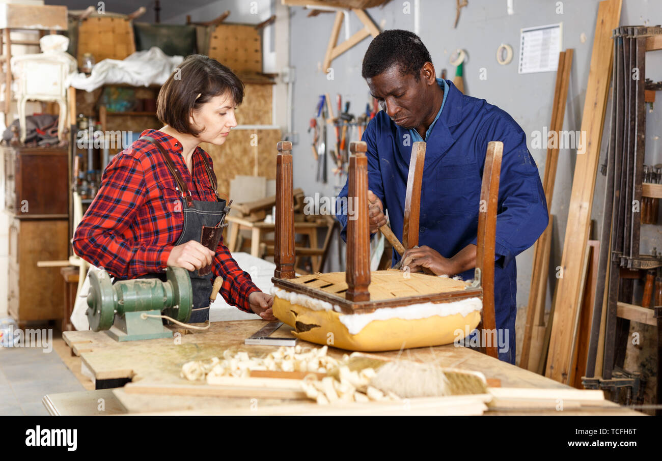 Woman and man carpenters inspecting old wooden chair in studio Stock ...