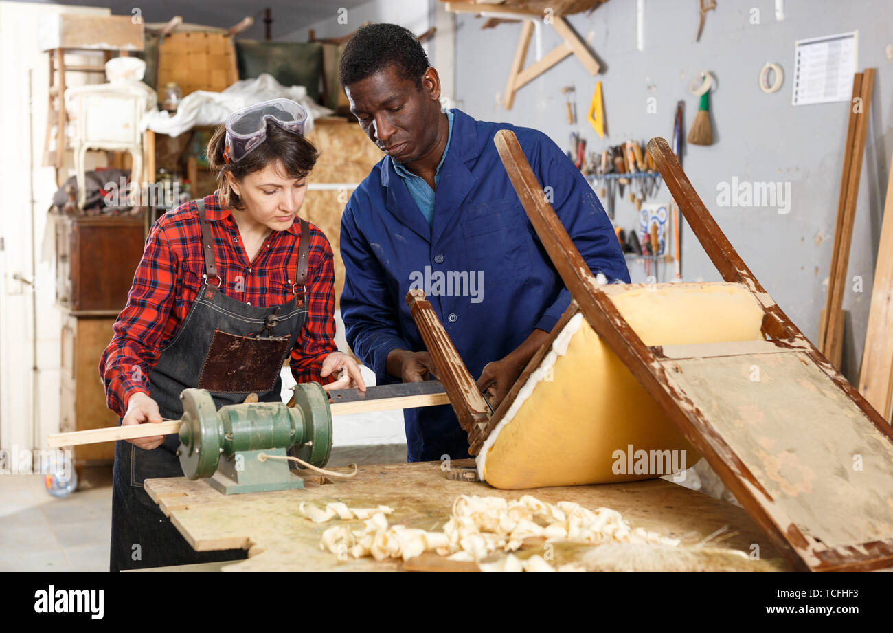 Woman and man carpenters using tools for restoration wooden chair in ...