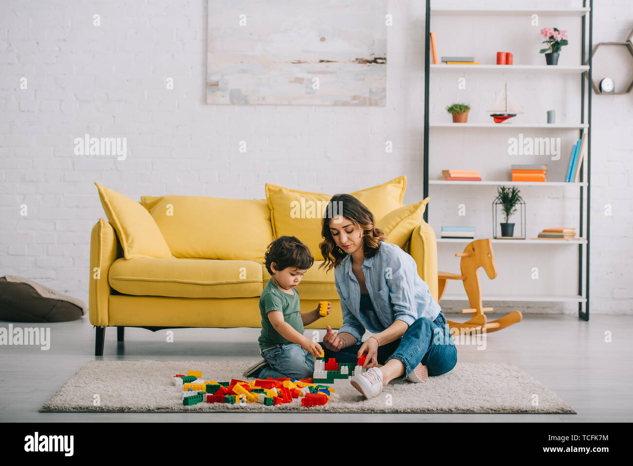Mother and son playing with lego on carpet in living room Stock Photo ...