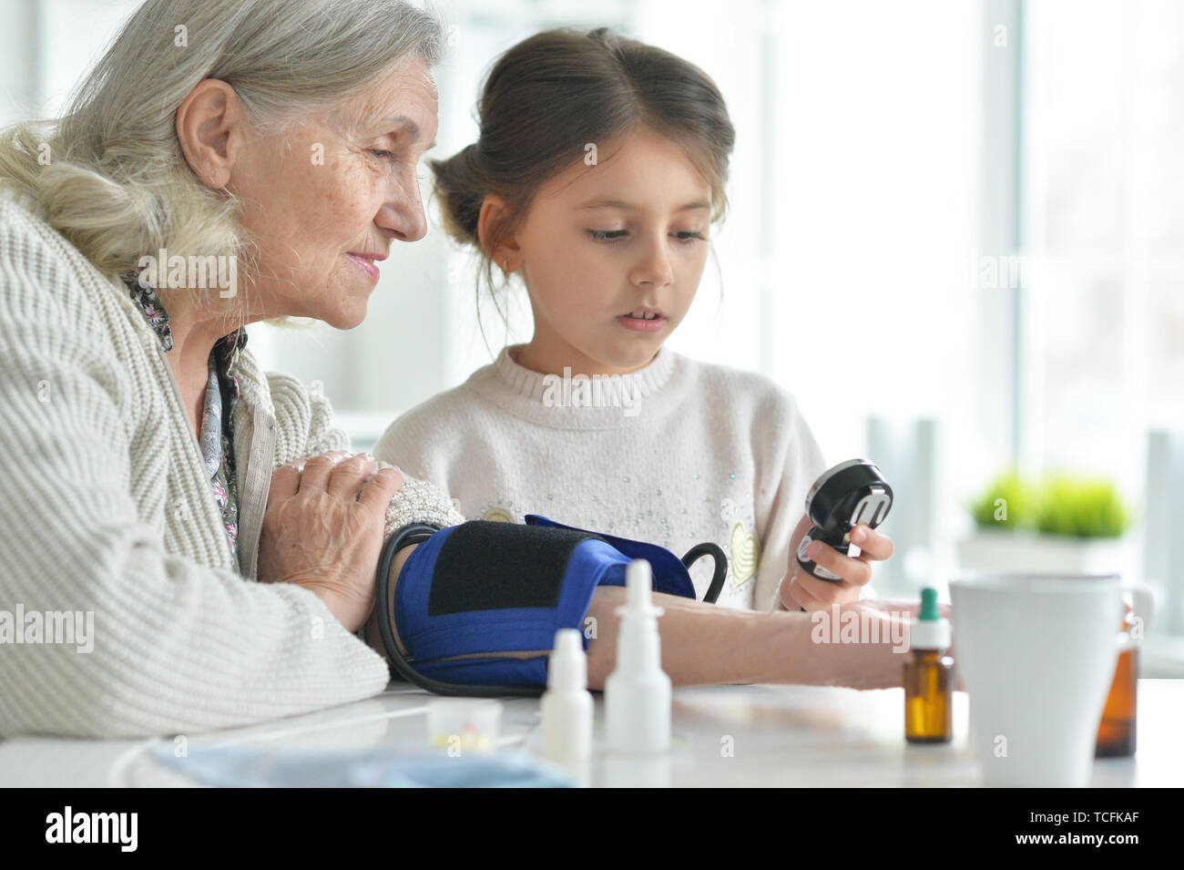 Cute girl and senior woman measuring blood pressure Stock Photo - Alamy