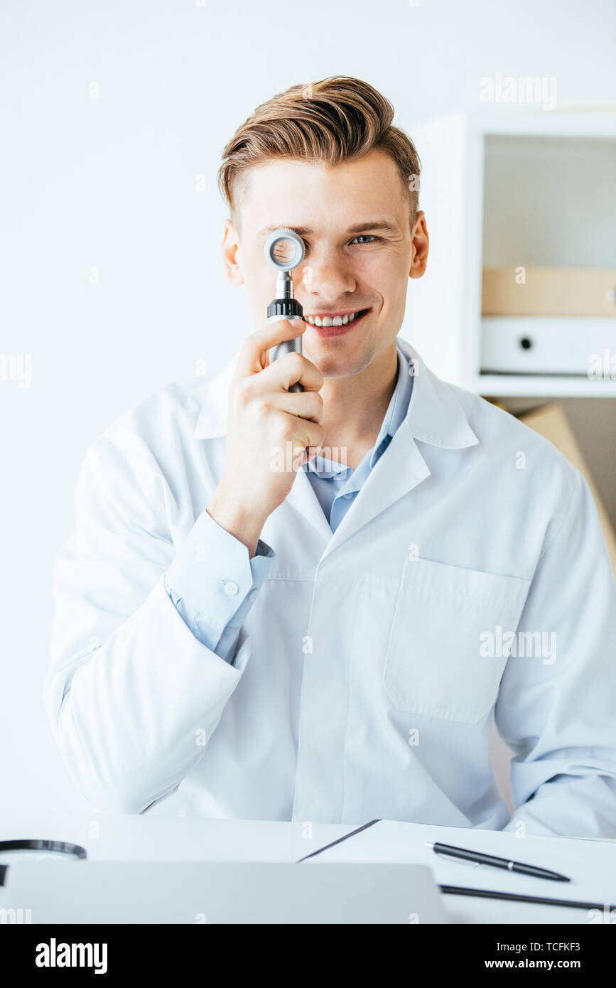 handsome dermatologist in white coat holding dermatoscope and smiling ...