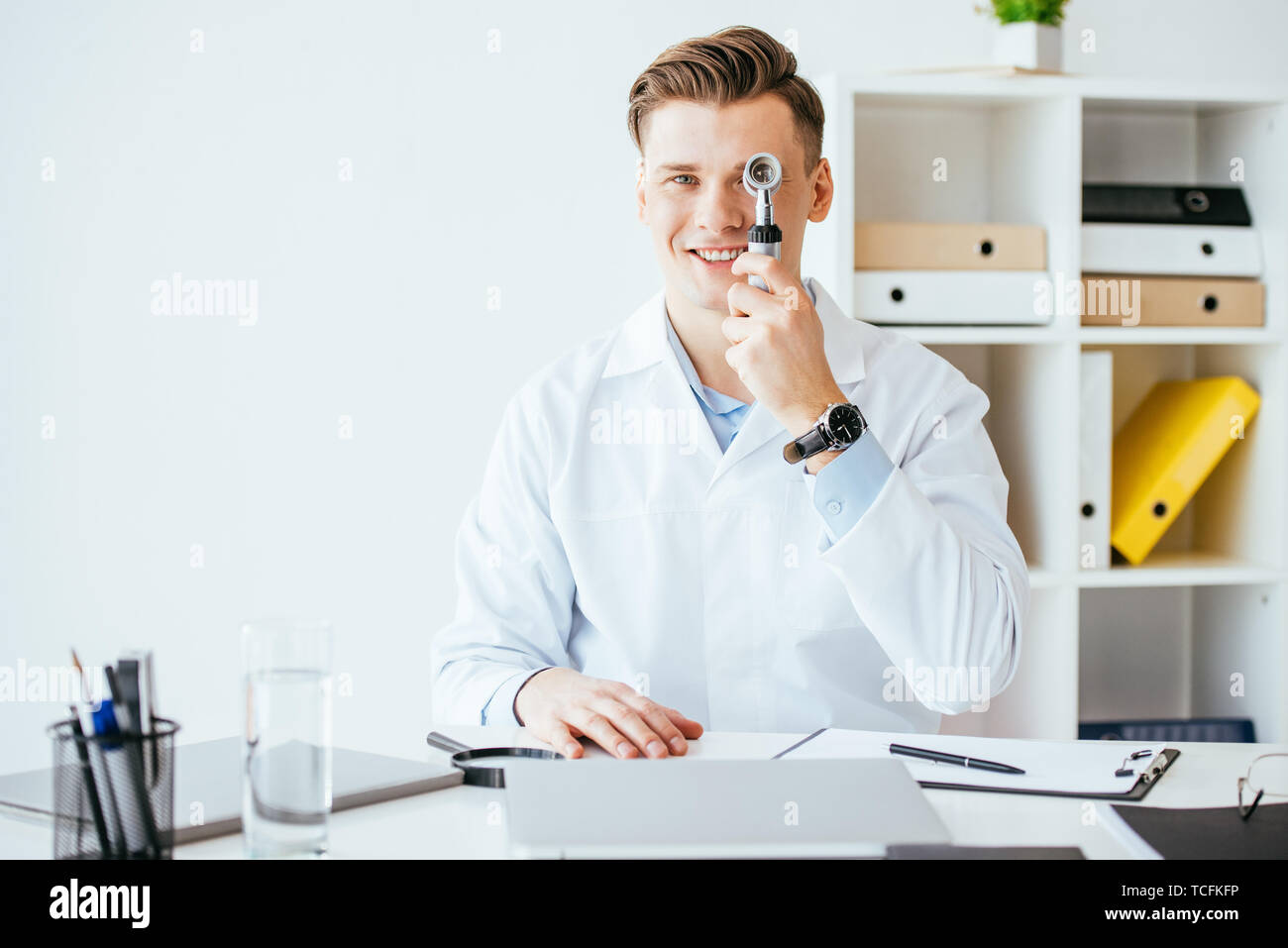 cheerful dermatologist in white coat holding dermatoscope and smiling ...
