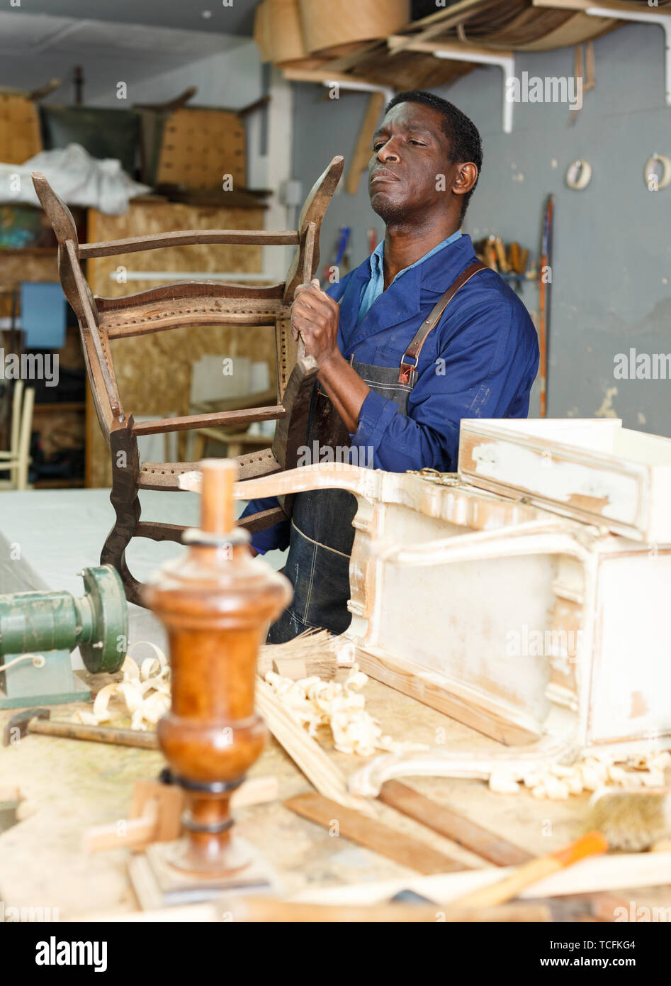 Portrait of furniture restorer in process of renewing vintage chair at ...