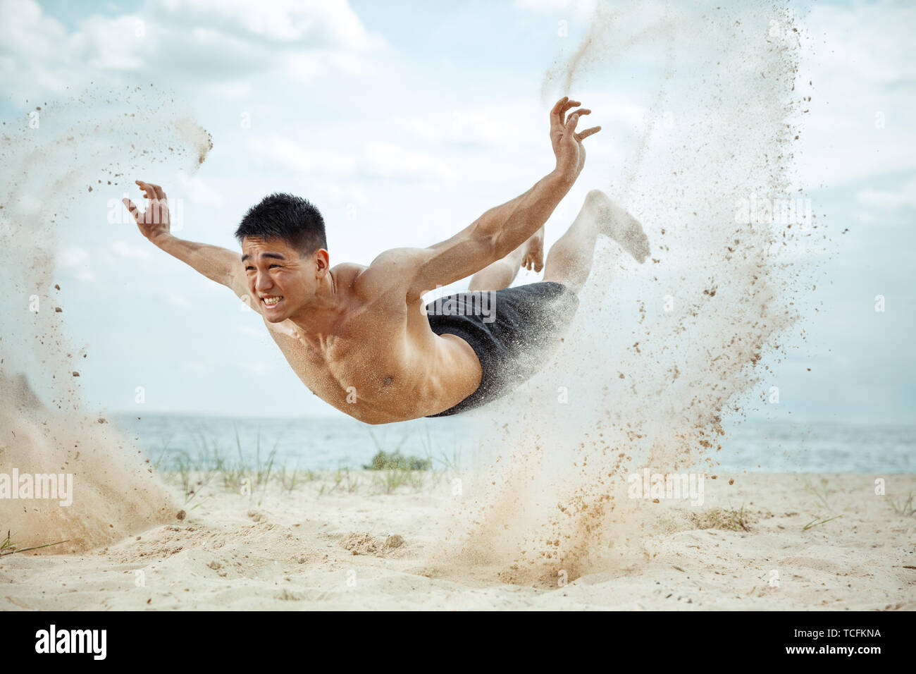 Weightless. Young healthy man athlete doing exercise at the beach ...