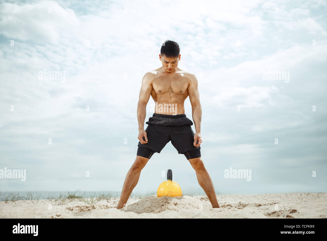 Young healthy man athlete doing exercise with the weight at the beach ...