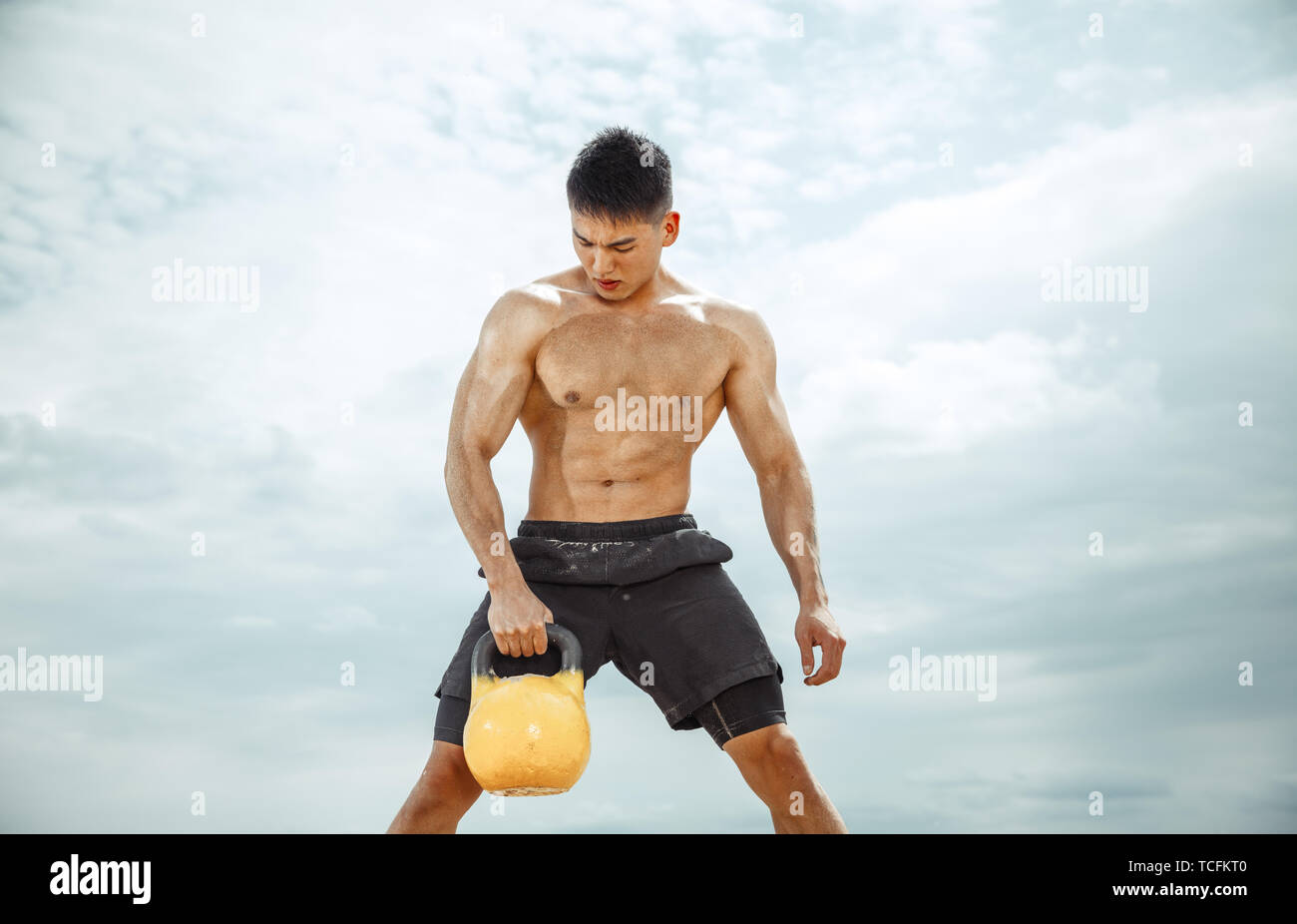 Young healthy man athlete doing exercise with the weight at the beach ...