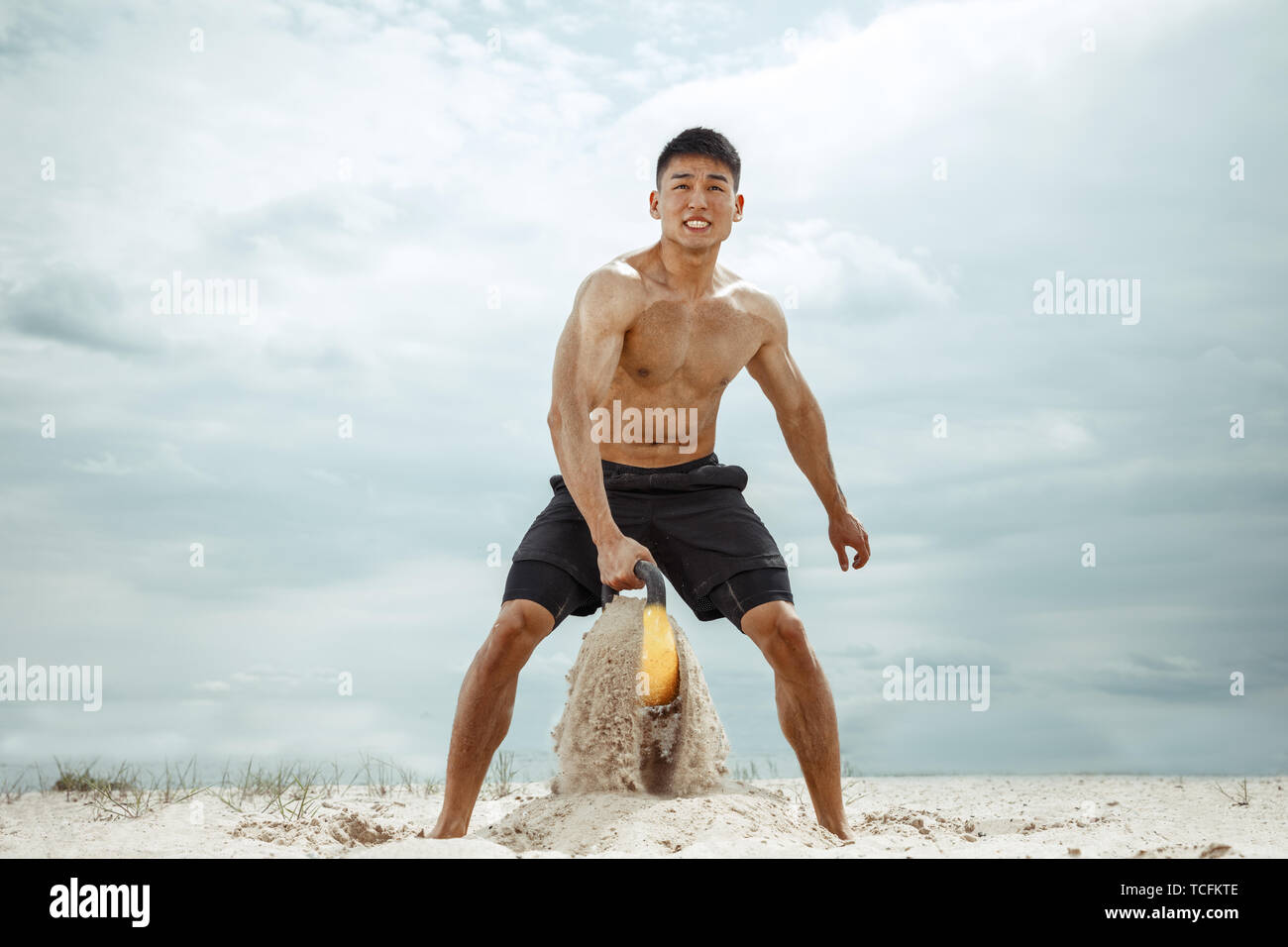Young healthy man athlete doing exercise with the weight at the beach ...