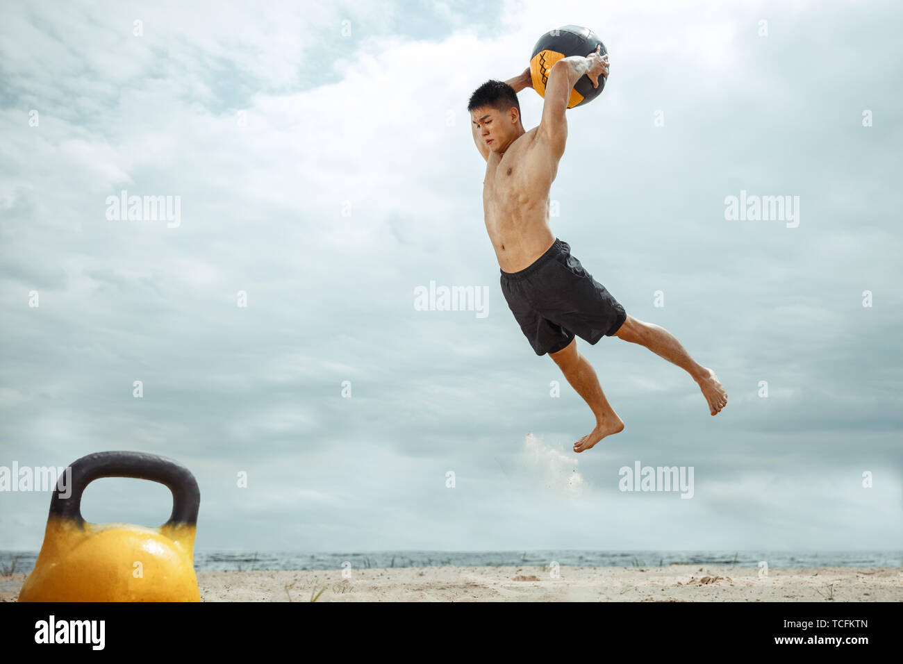 Young healthy man athlete doing exercise with the weight and ball at ...