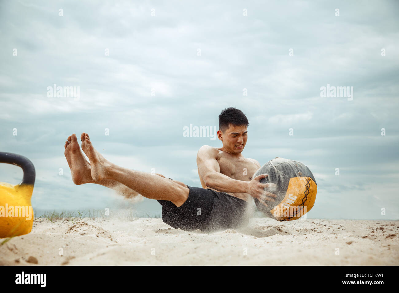 Young healthy man athlete doing exercise with the weight and ball at ...