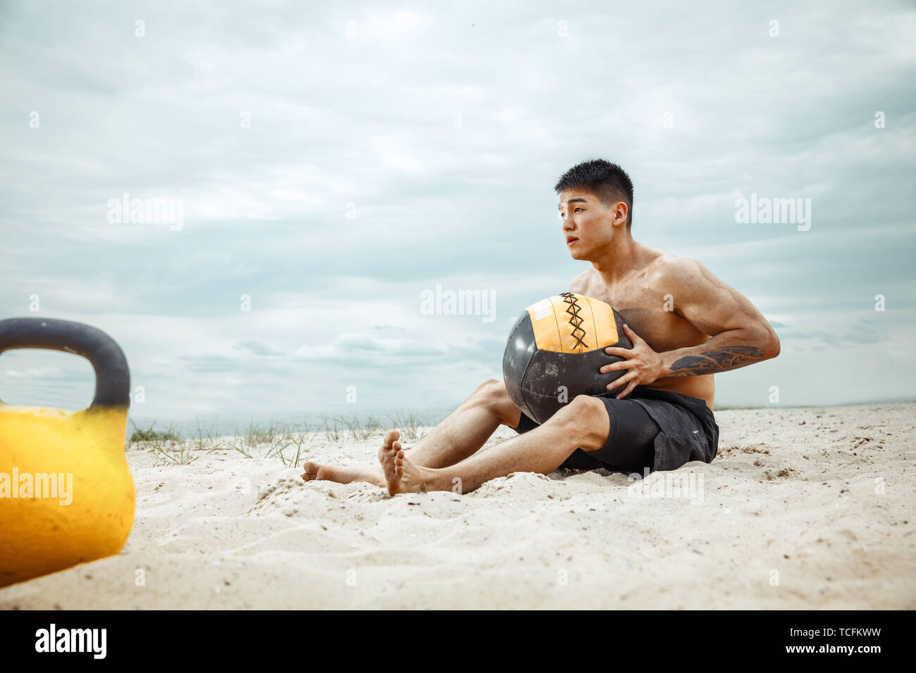 Young healthy man athlete doing exercise with the weight and ball at ...