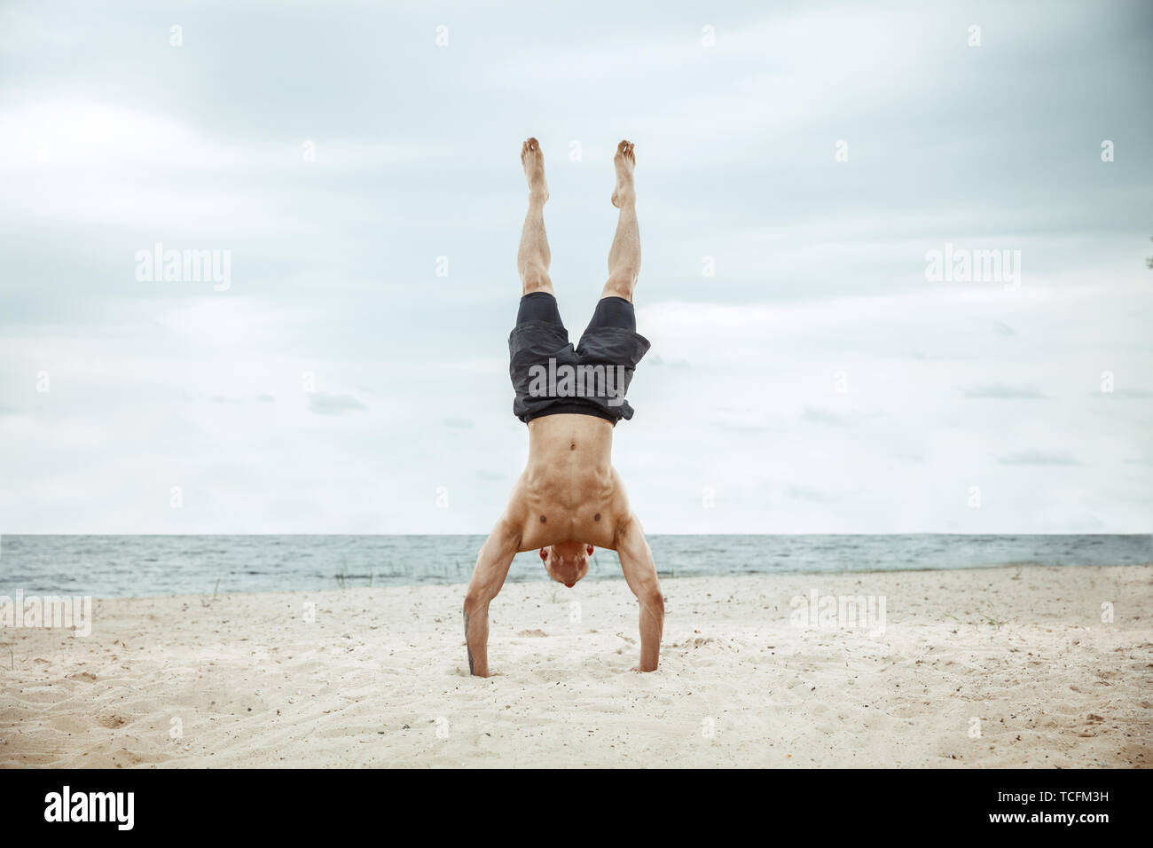 Young healthy man athlete doing exercise at the beach. Signle male ...