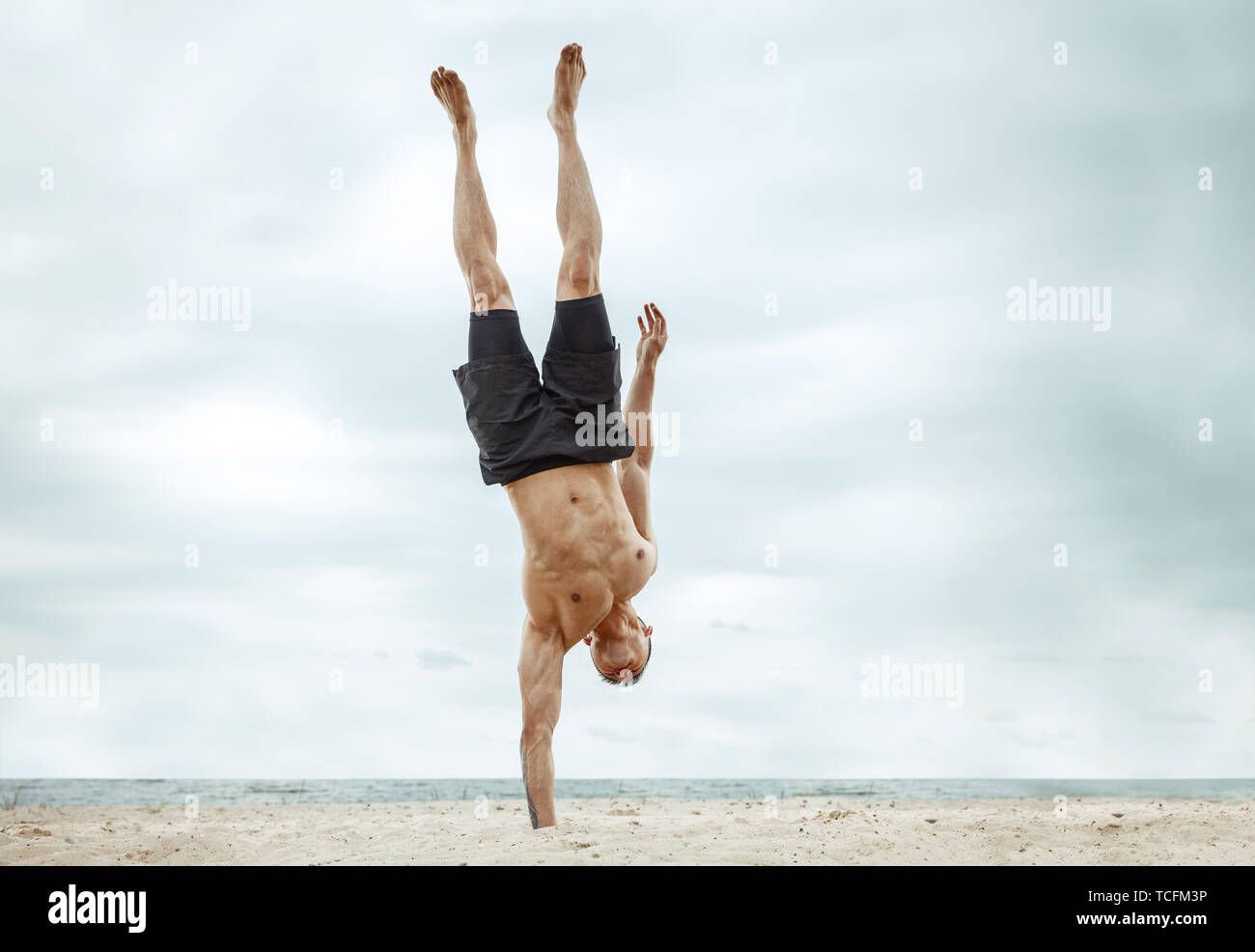 Young healthy man athlete doing exercise at the beach. Signle male ...