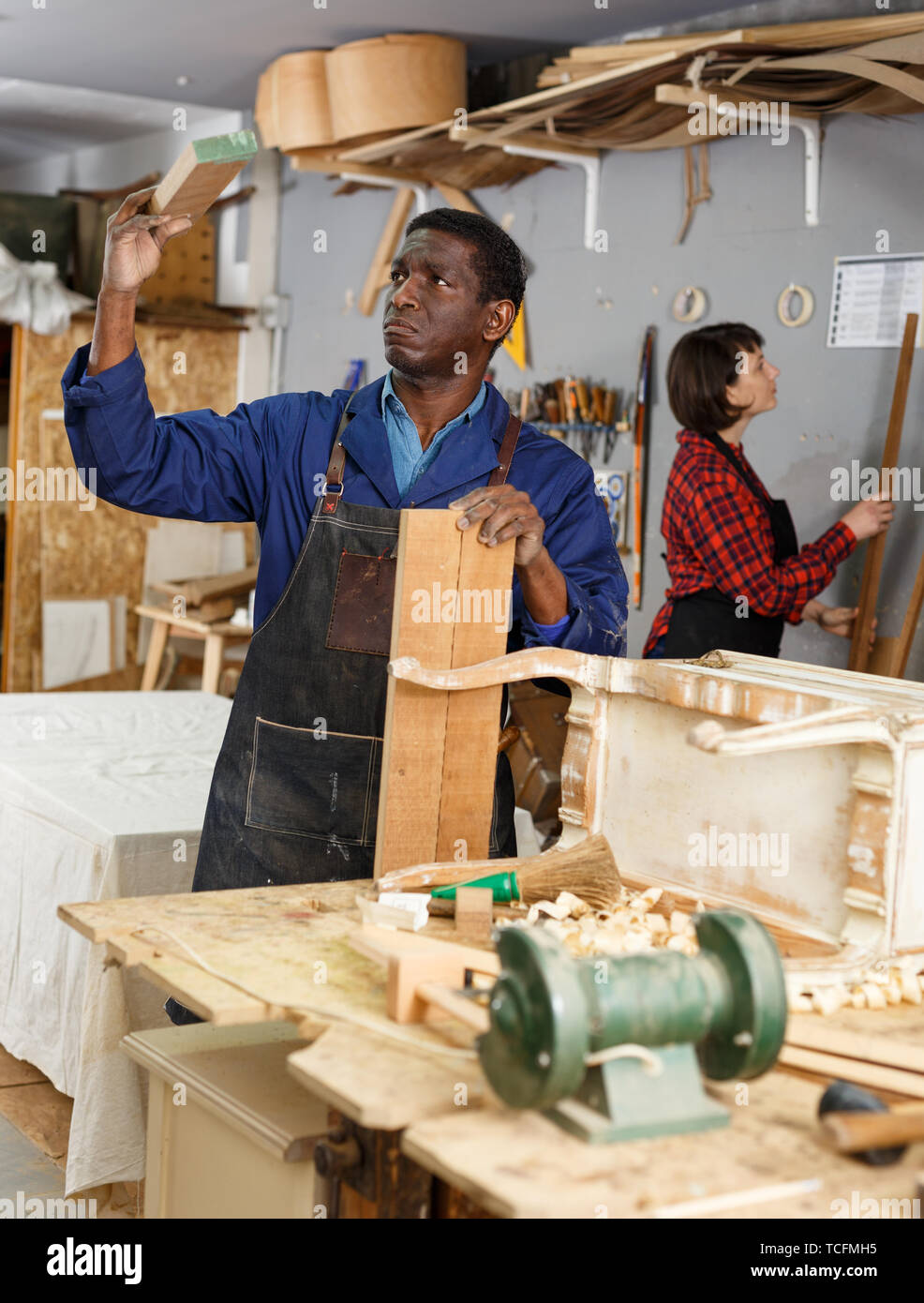 Woman and man carpenters using tools for restoration wooden bureau in ...