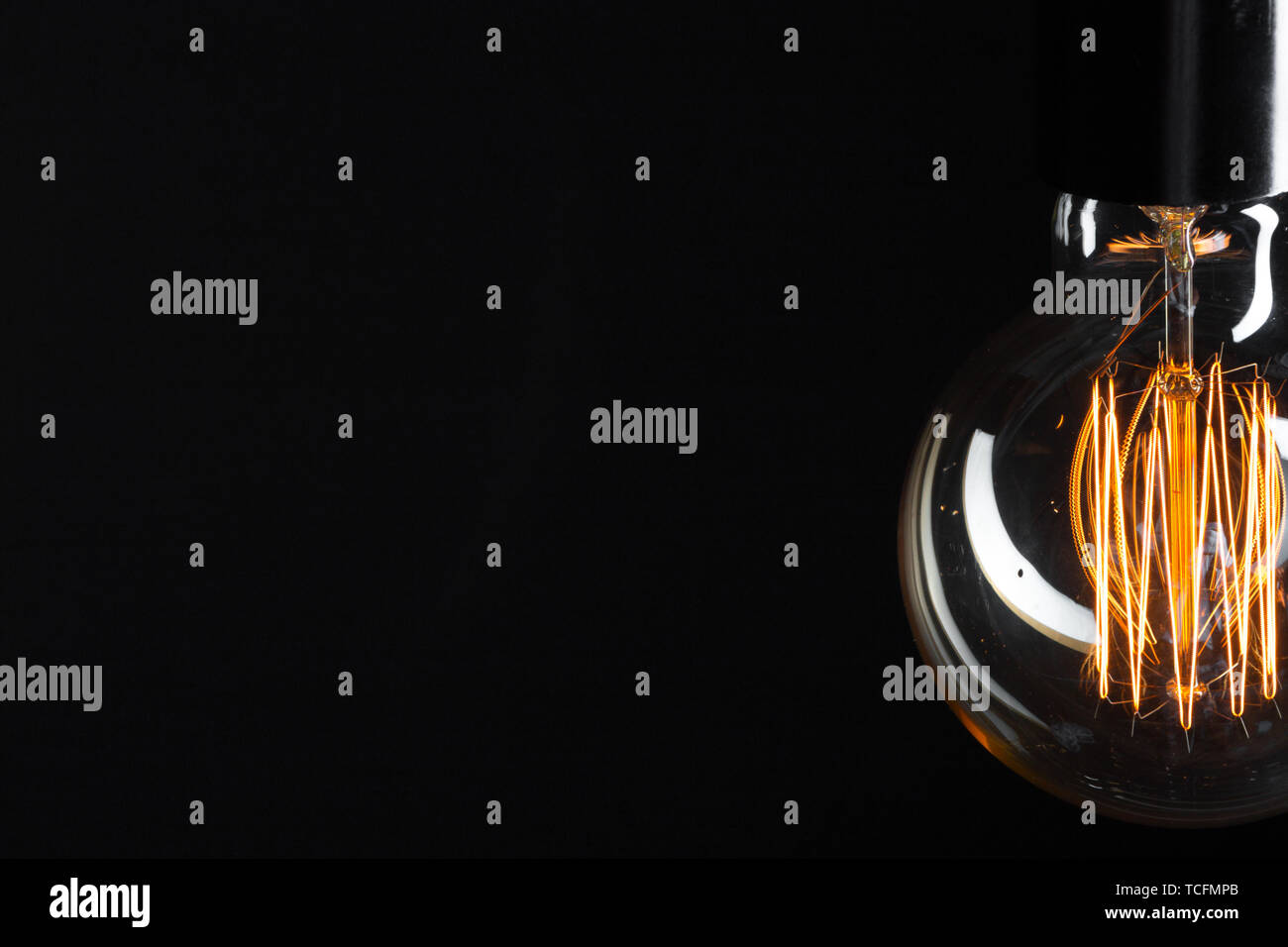 A classic Edison light bulb on dark background with space for text ...