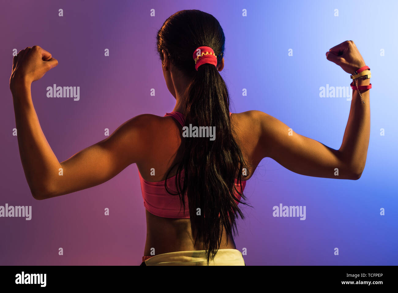back view of athletic african american girl on purple and blue gradient ...