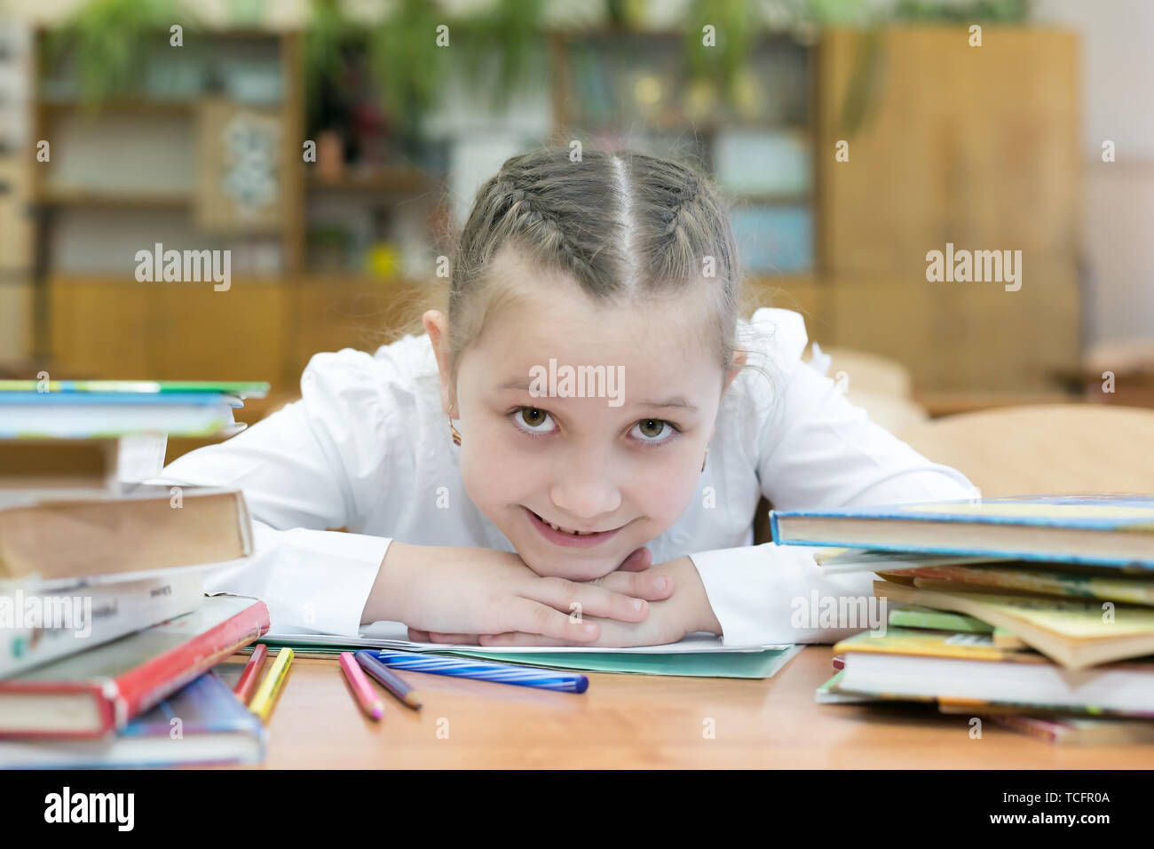 A tired teen schoolgirl is resting on a lesson lying leaning on her ...
