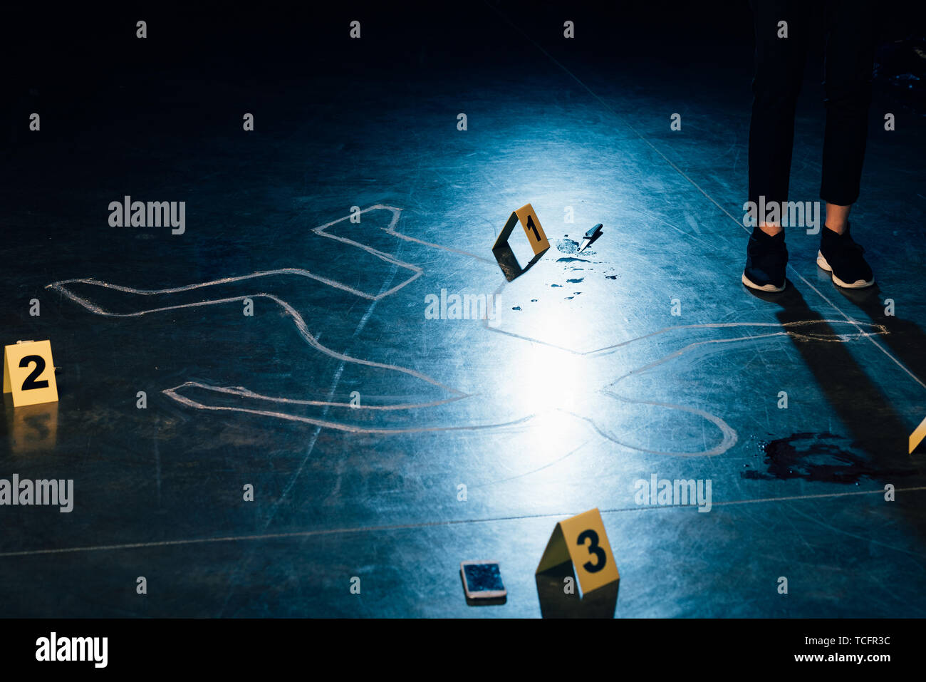 partial view of investigator standing near chalk outline and evidence ...